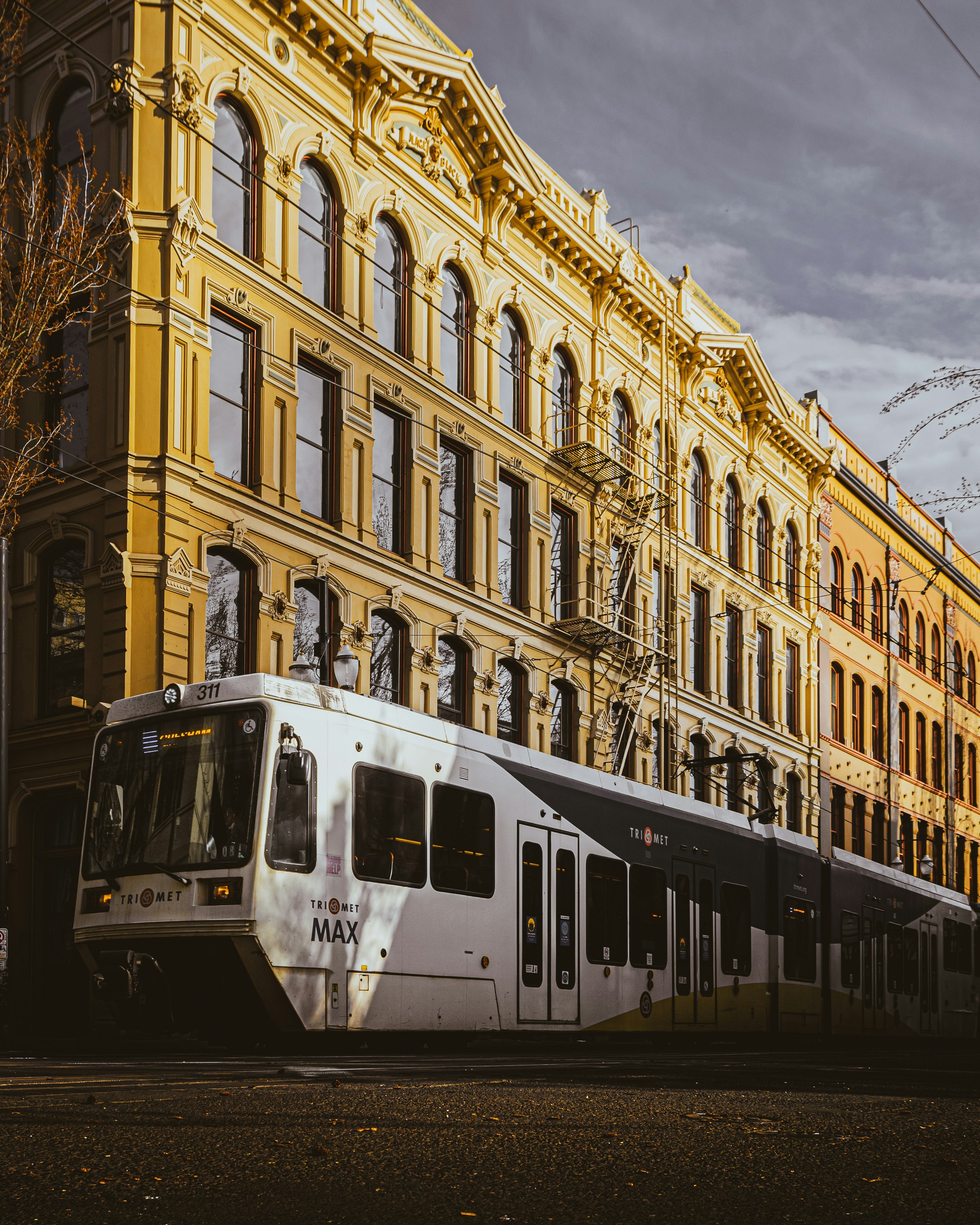 Light rail train gliding past historic architecture, showcasing the blend of modern transit and classic design.