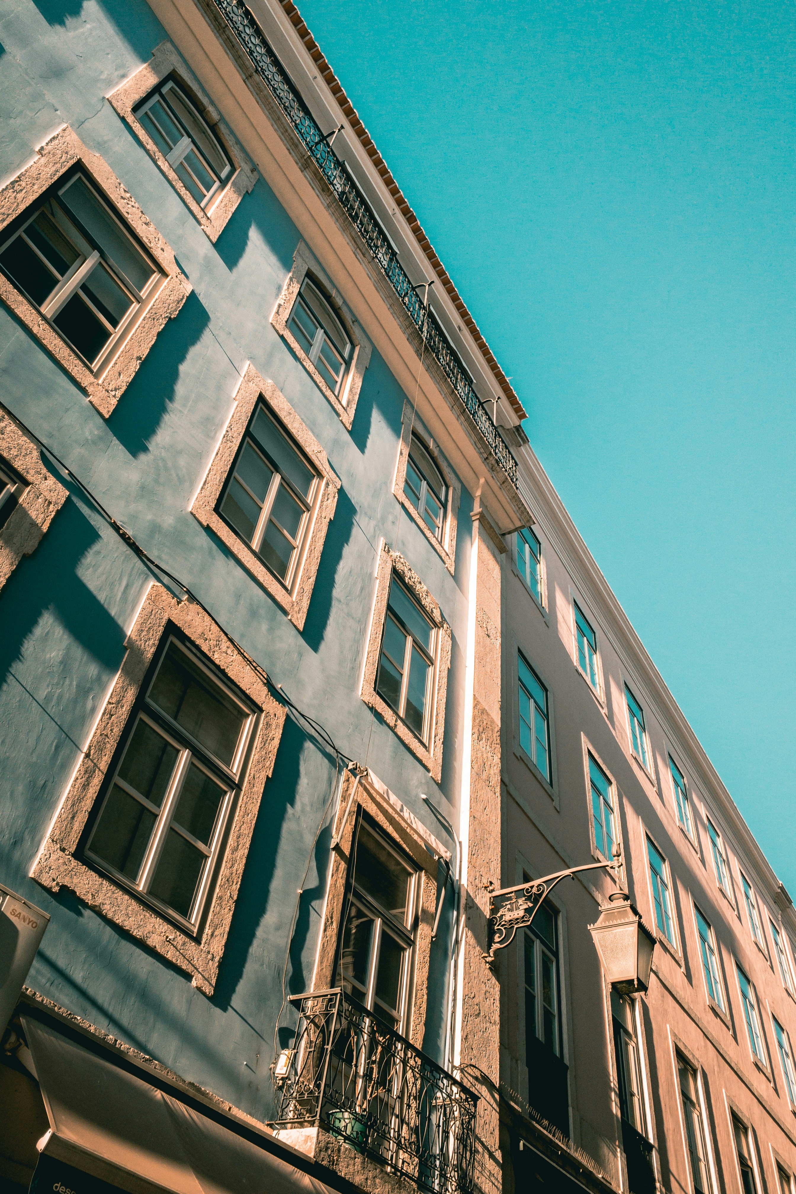 Architectural details of a pastel blue building with ornate balconies and sunlight casting intricate shadows.