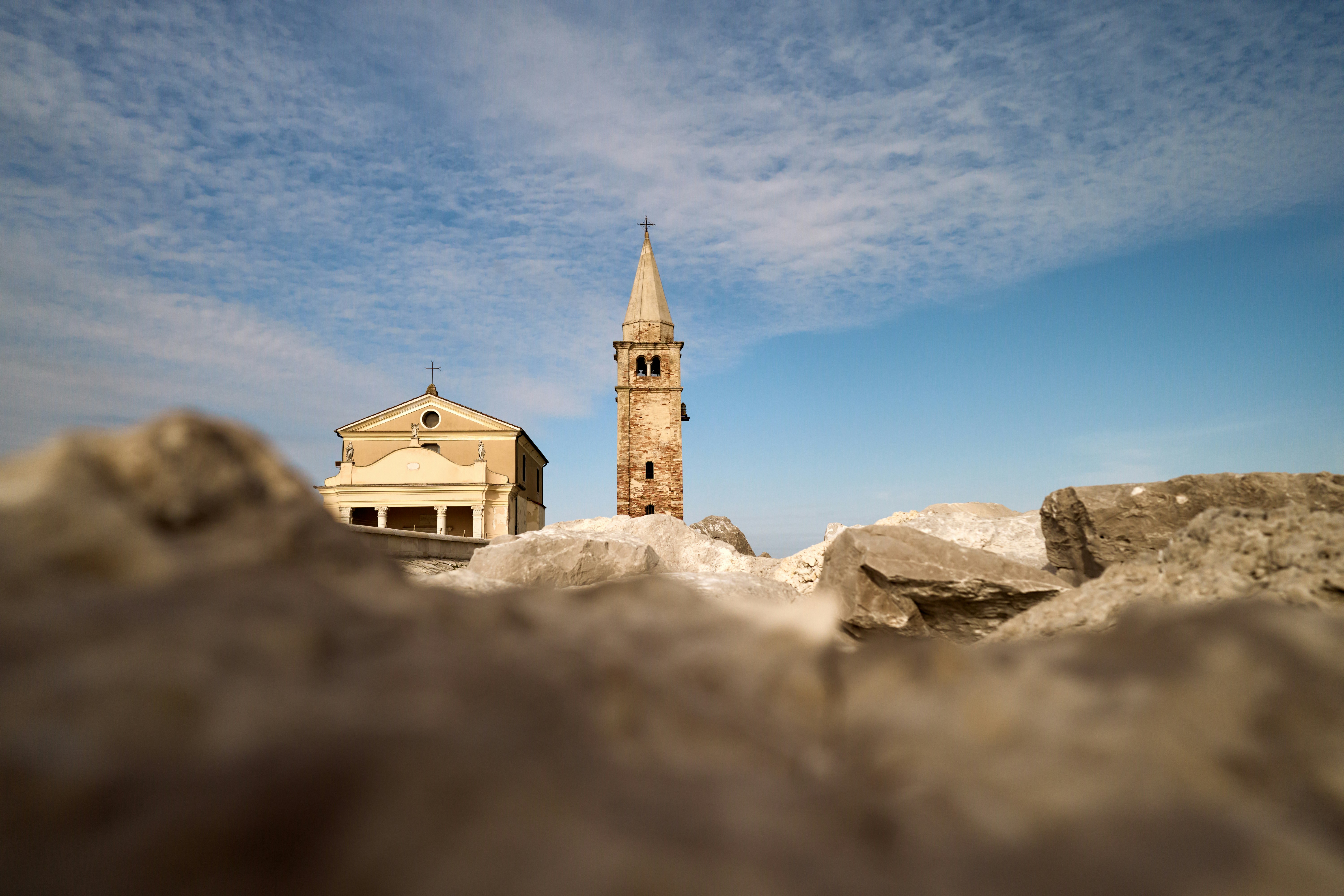 Stone Foreground, Skyward Spire: A Coastal Chapel Rises from the Rugged Shore