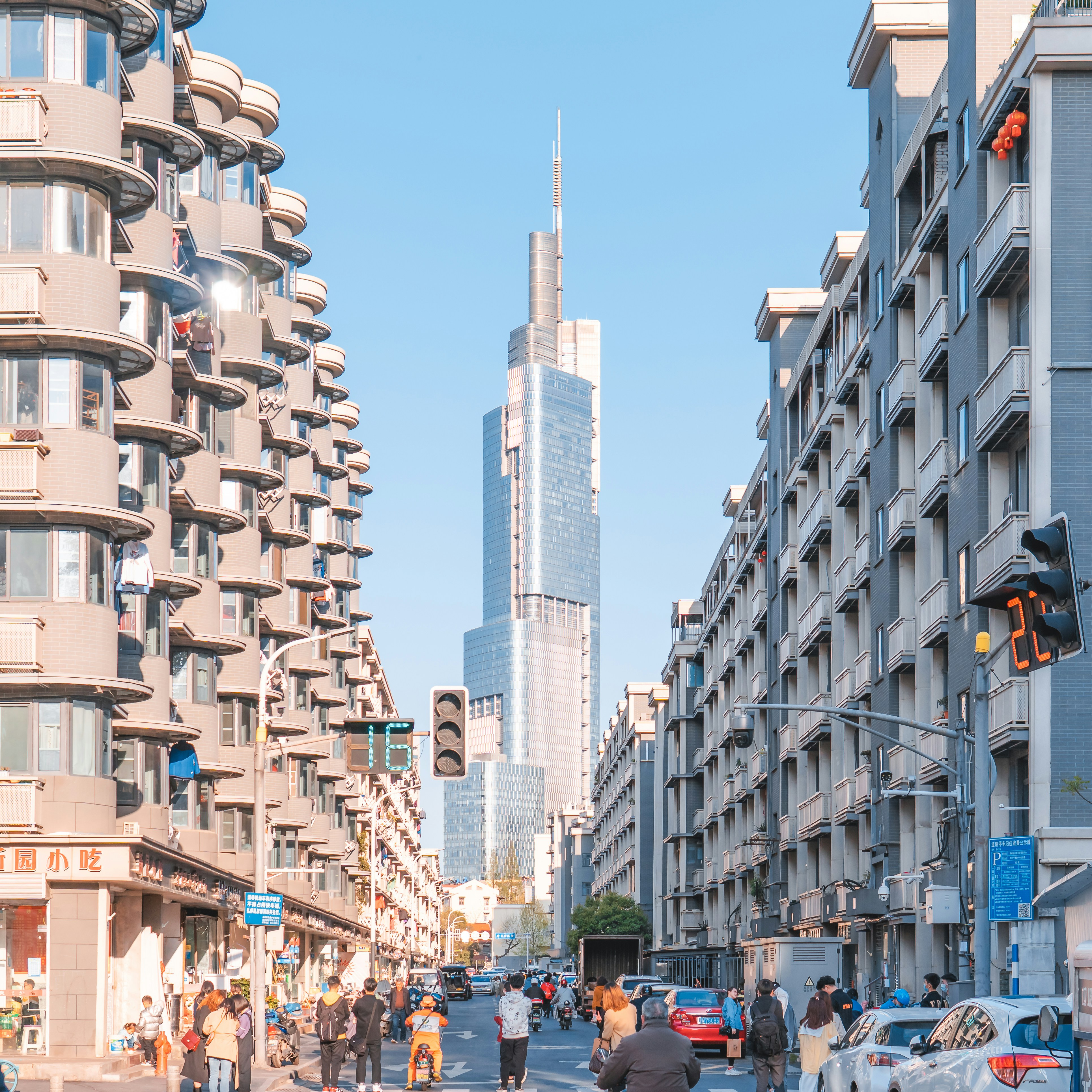 Modern skyscraper rises amidst a bustling urban street scene, showcasing the blend of architecture and daily life.