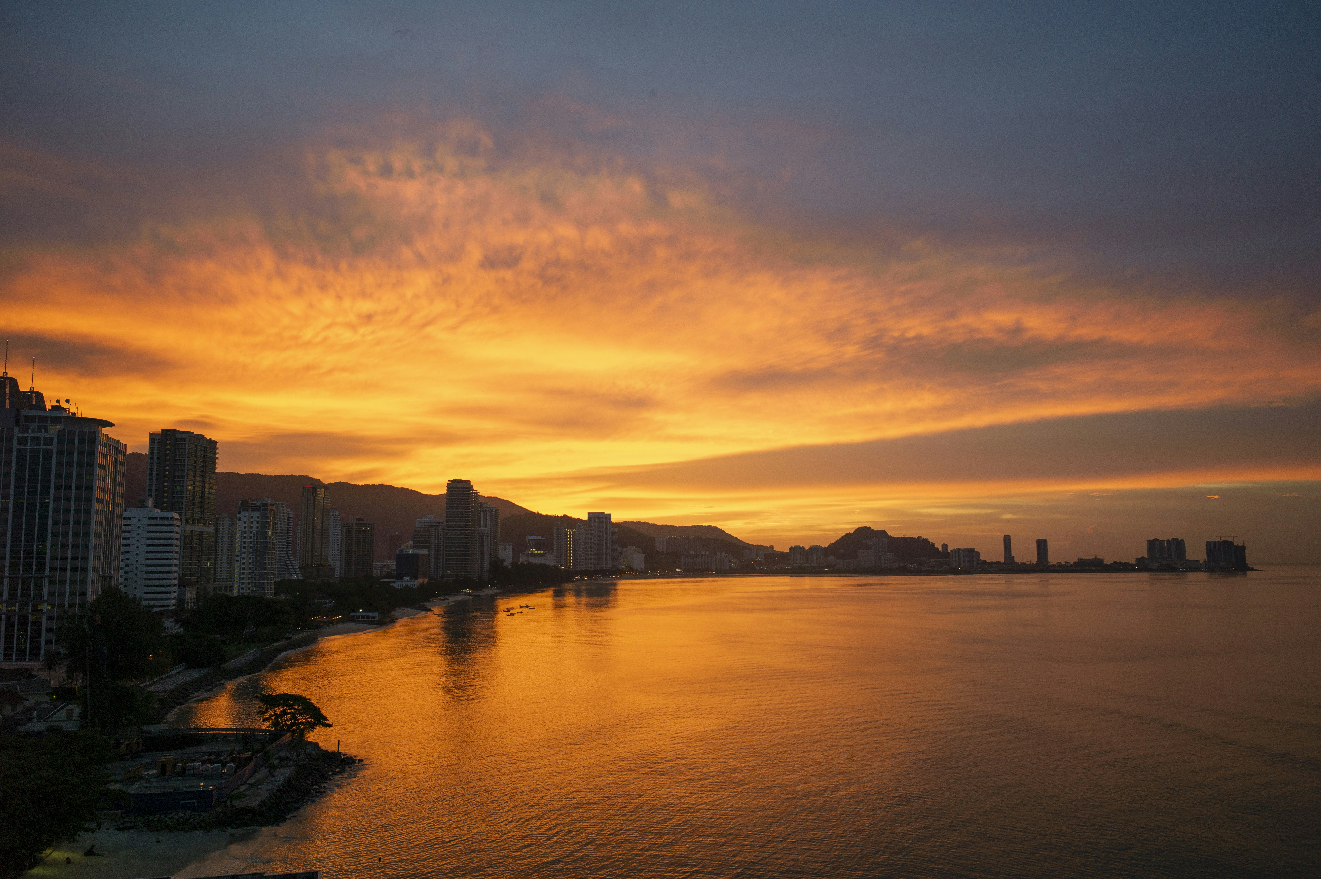 Horizon Fire: Sunset Over a Calm Bay and City Silhouette