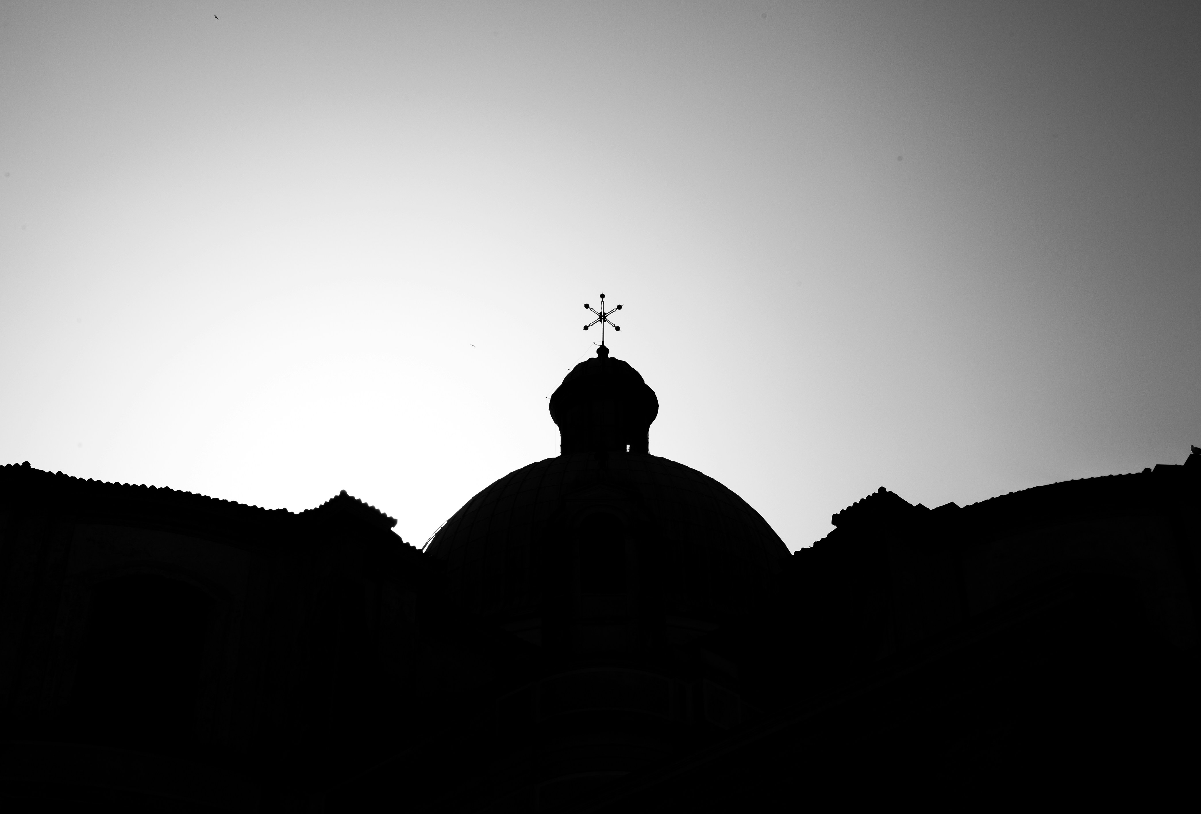 Dome Crowned by a Cross Against a Backlit Horizon