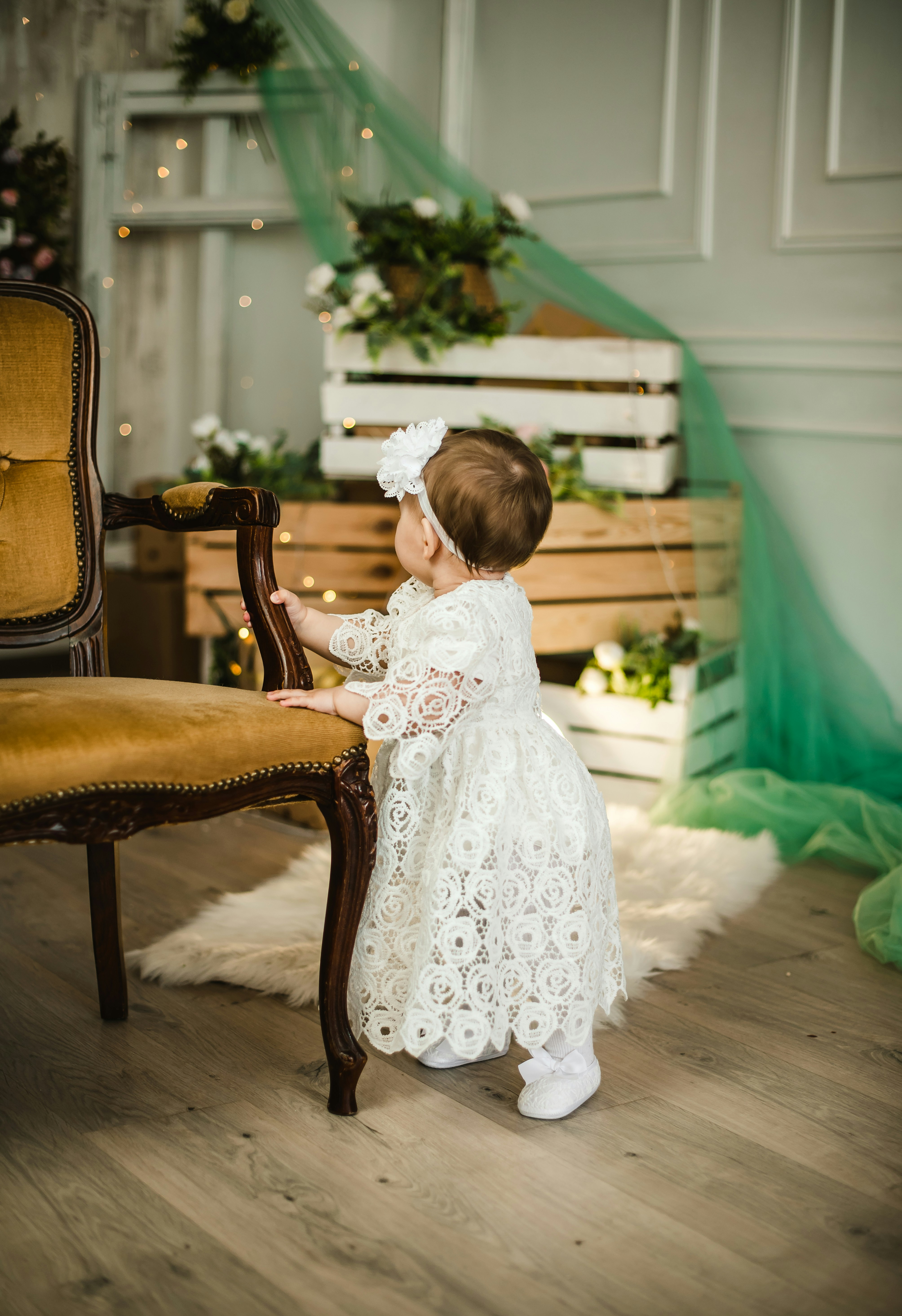 Lace-Clad Toddler Finds Balance at a Vintage Chair Amid Greenery