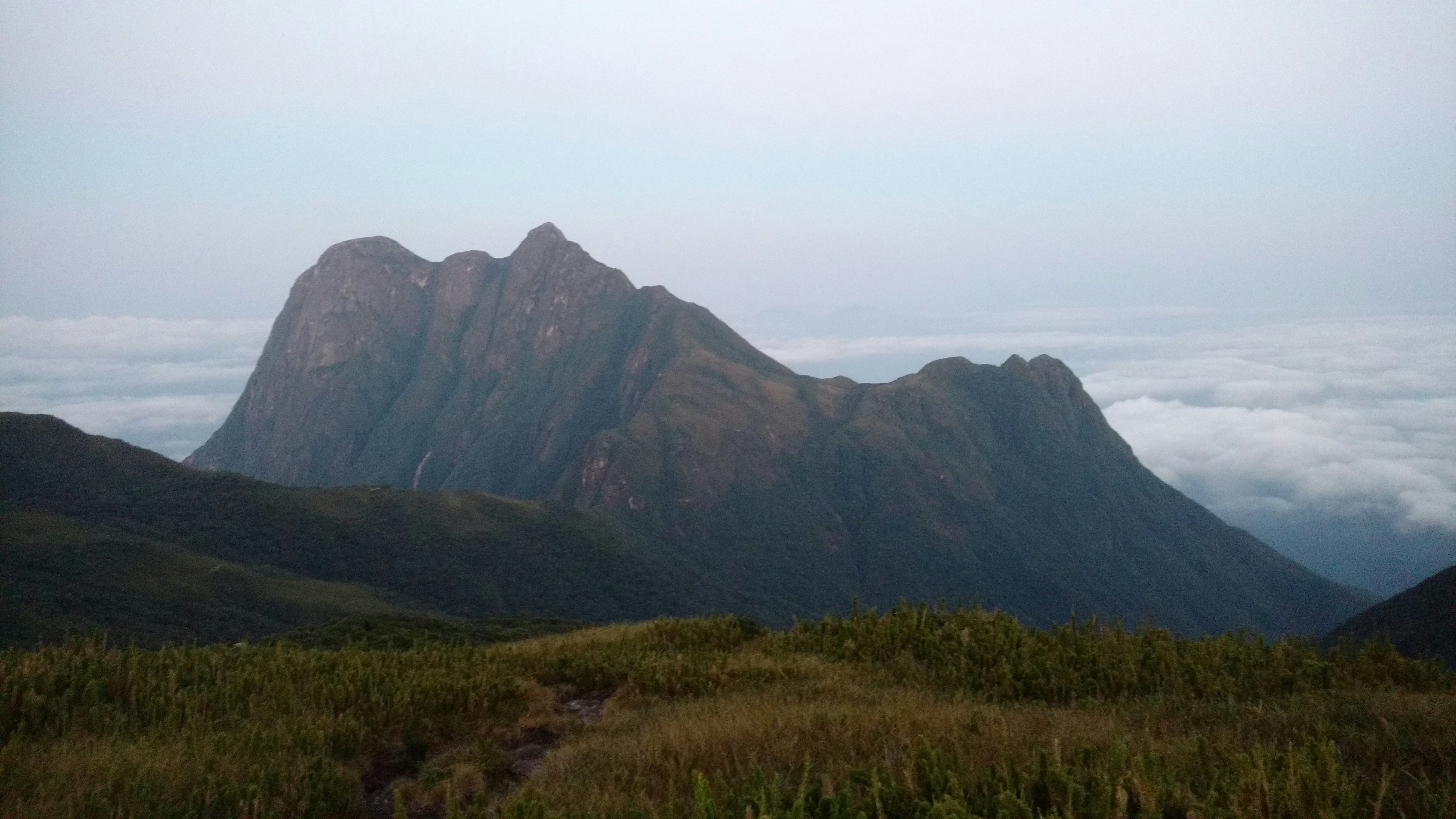 Mountain range beneath a blanket of clouds during early morning light.