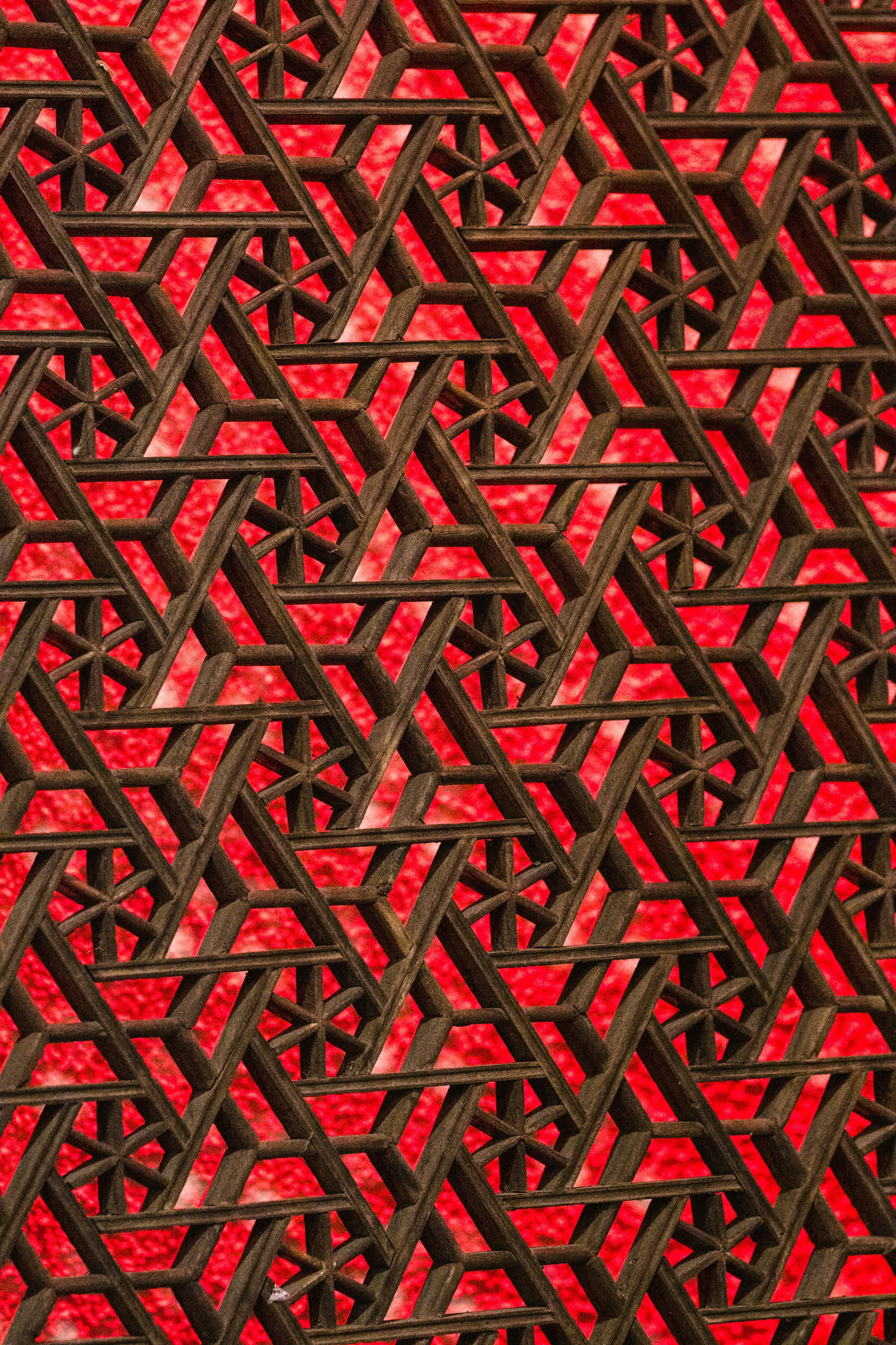 Crisscross Ember: close-up of a rusted metal lattice over a red textured background