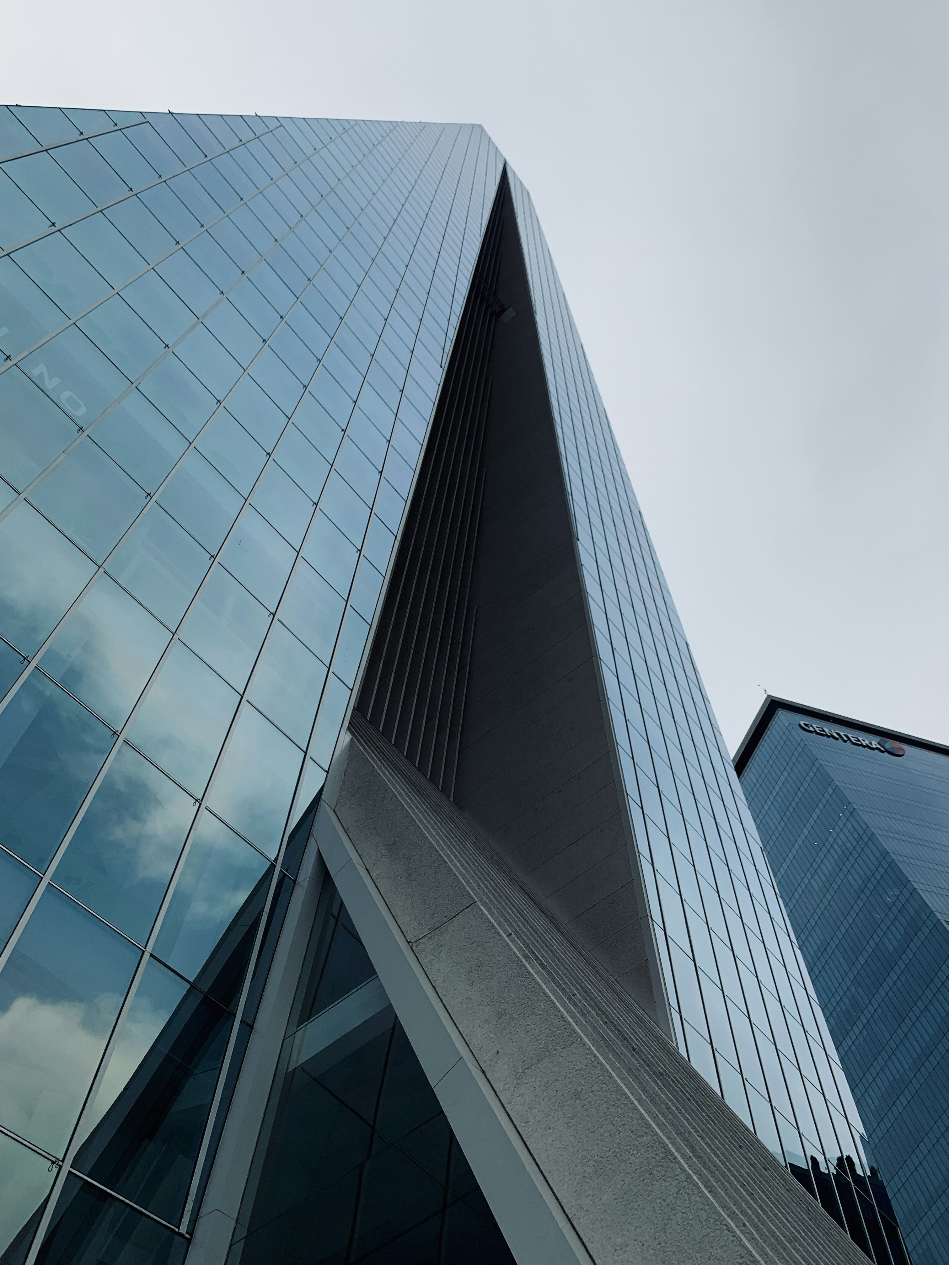 A sleek, angular skyscraper with reflective glass surfaces, showcasing a modern architectural design against a cloudy sky.