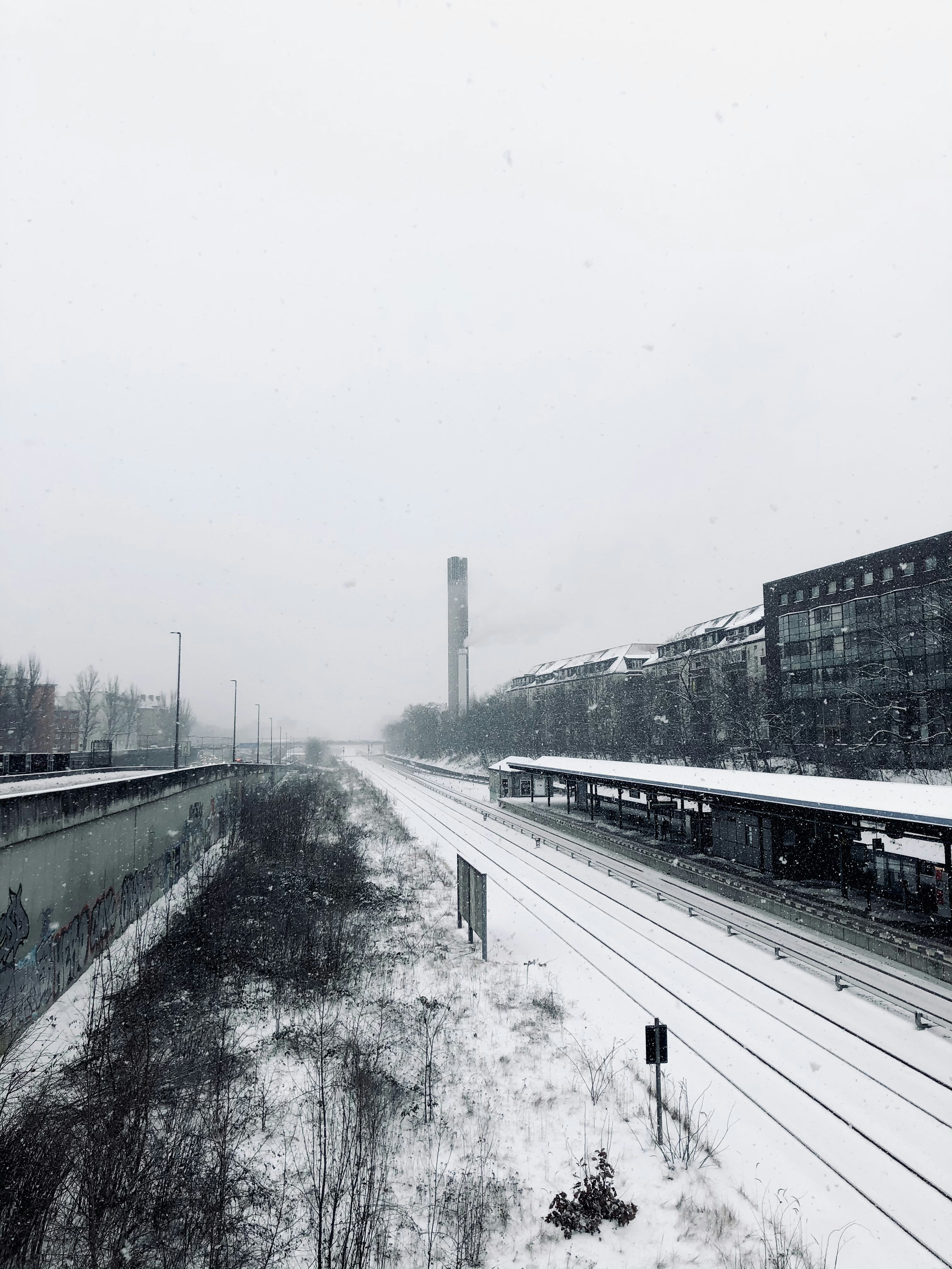 Snowbound Rails: A Distant Chimney Emerges Along the Quiet Track