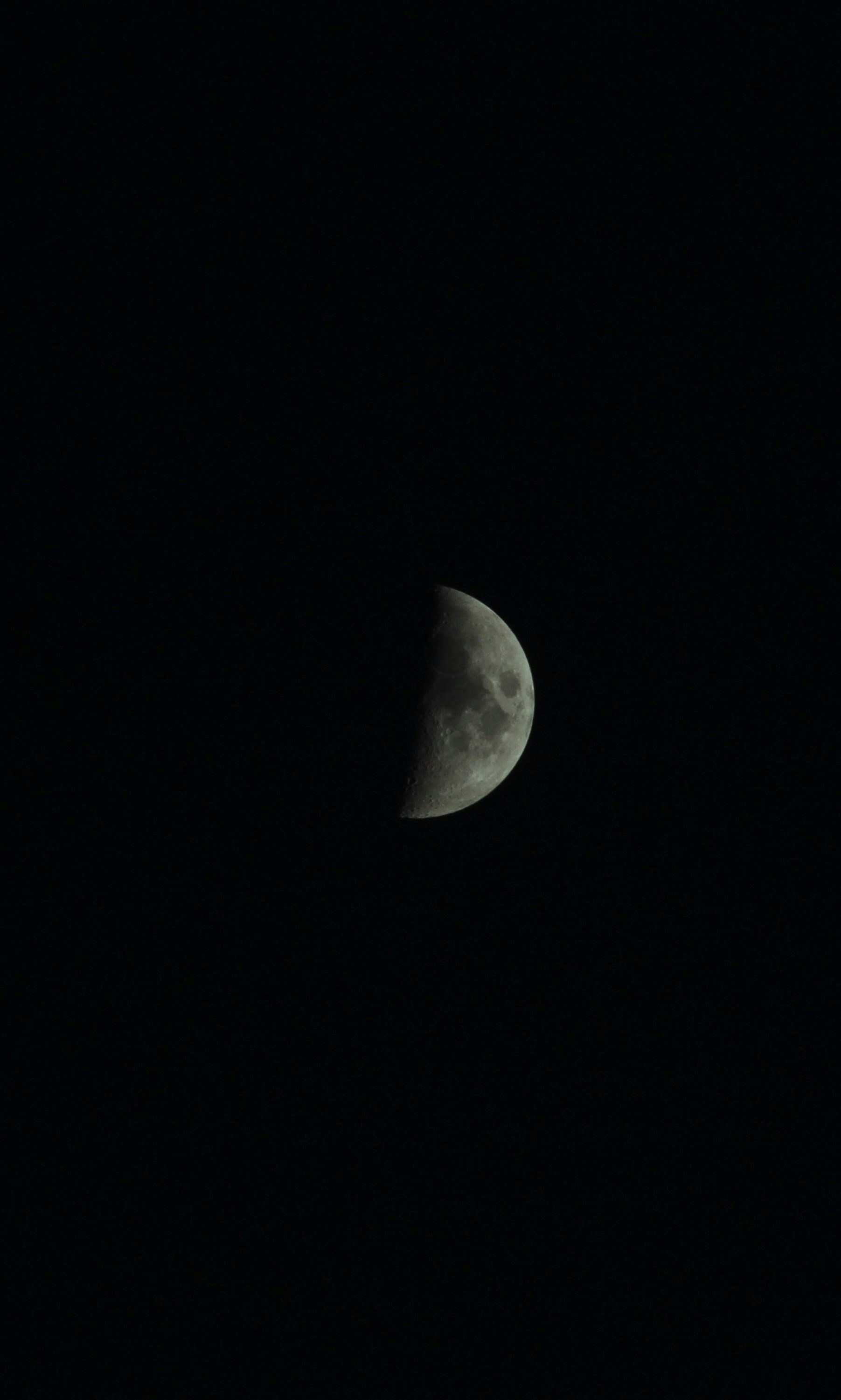 Waxing crescent moon partially illuminated against a deep black sky, revealing its craters and surface texture.