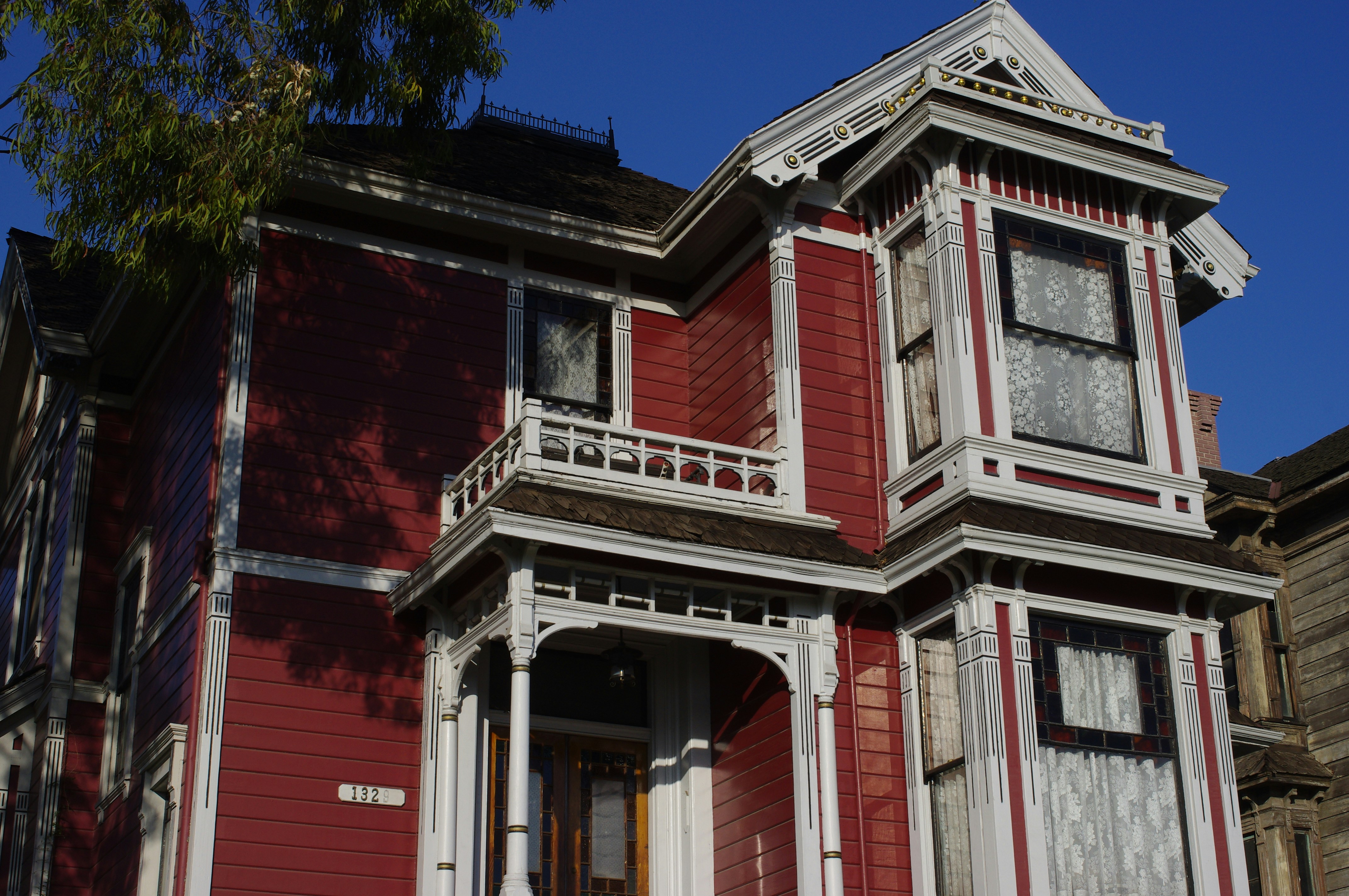 Intricately designed Victorian house with vibrant red siding and ornate trim, showcasing historical architectural details.