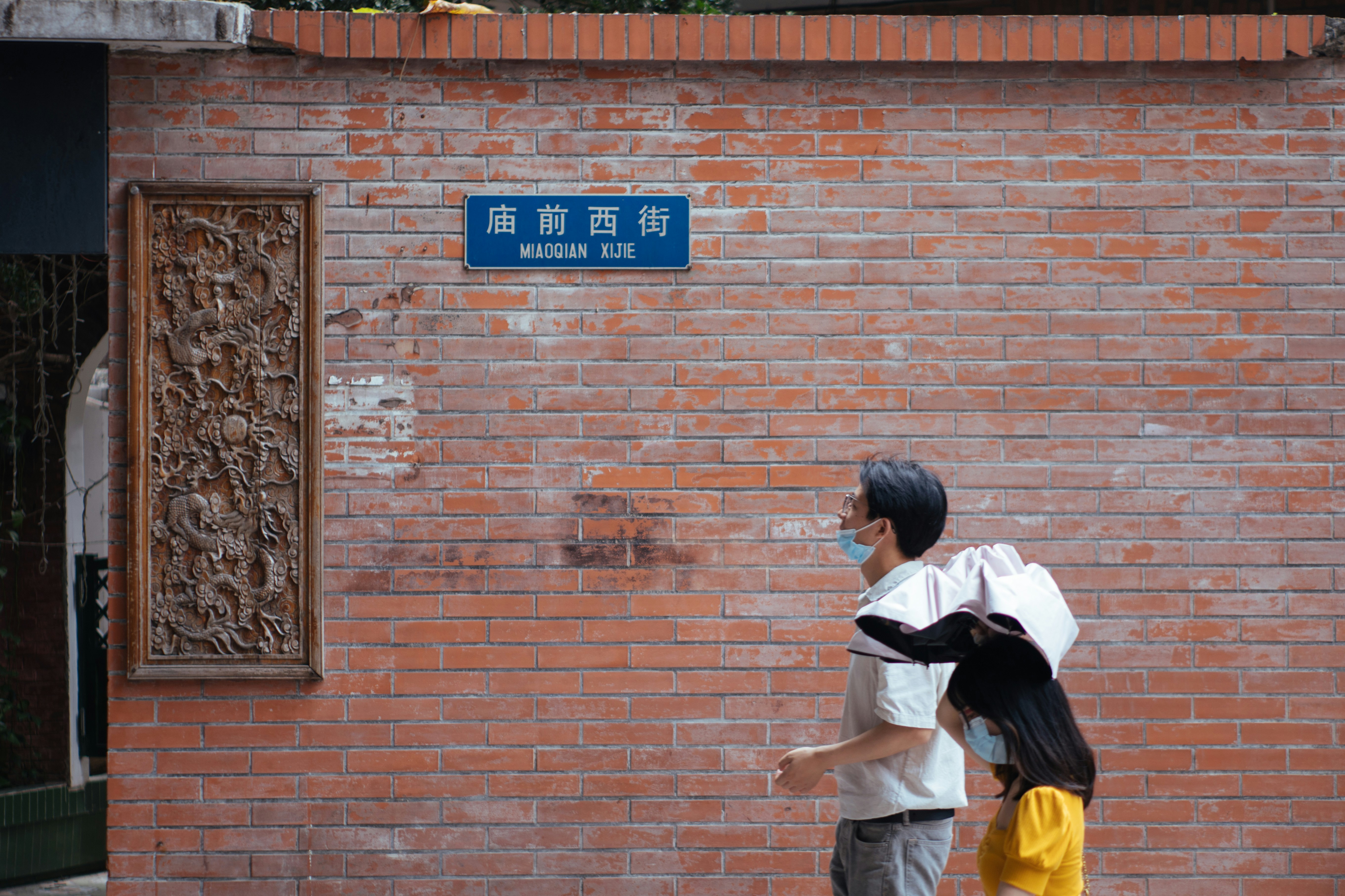 Masked Moment on a Brick-Lined Street by a Carved Panel