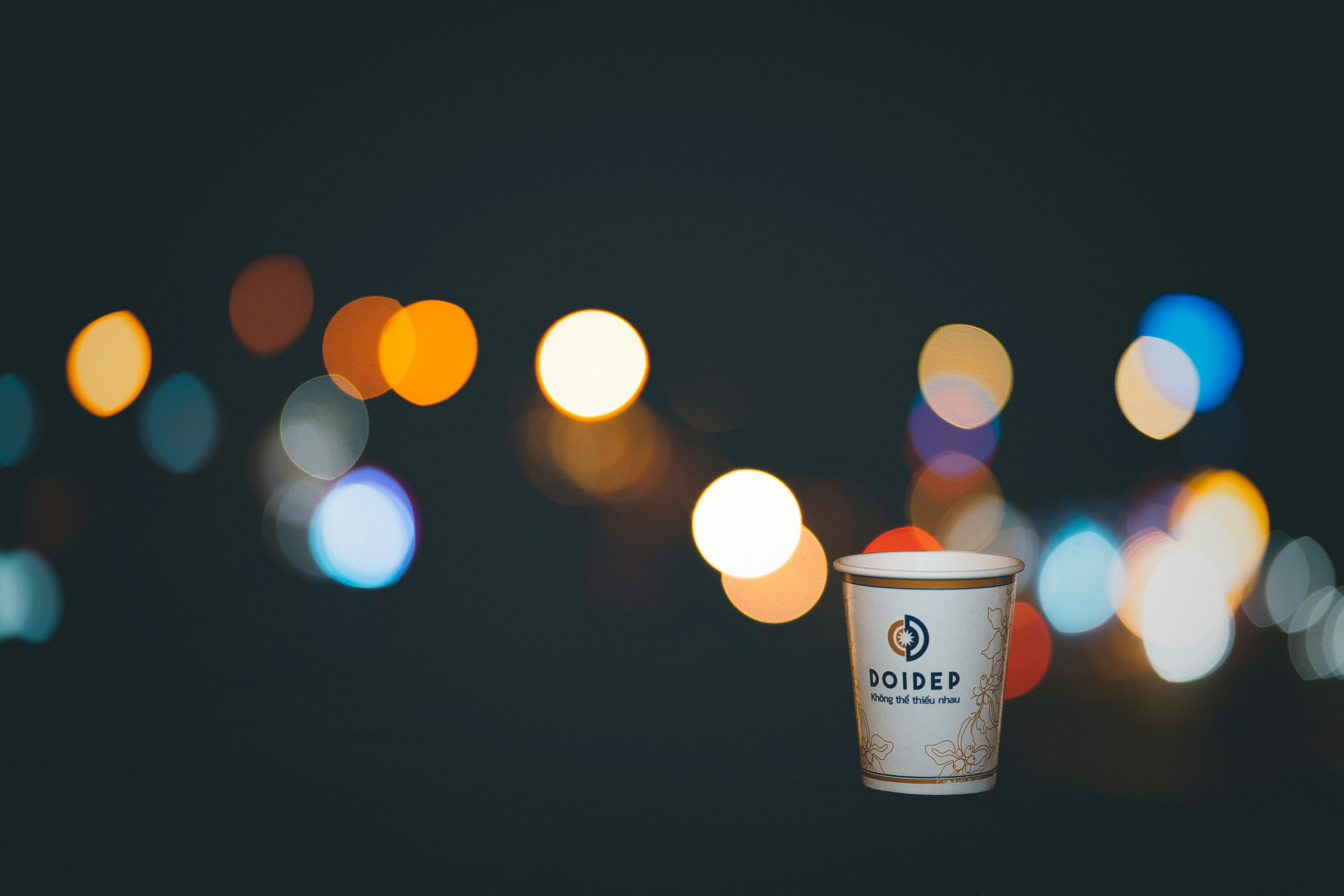 Neon Quiet: A Single Coffee Cup Pierced by City Lights