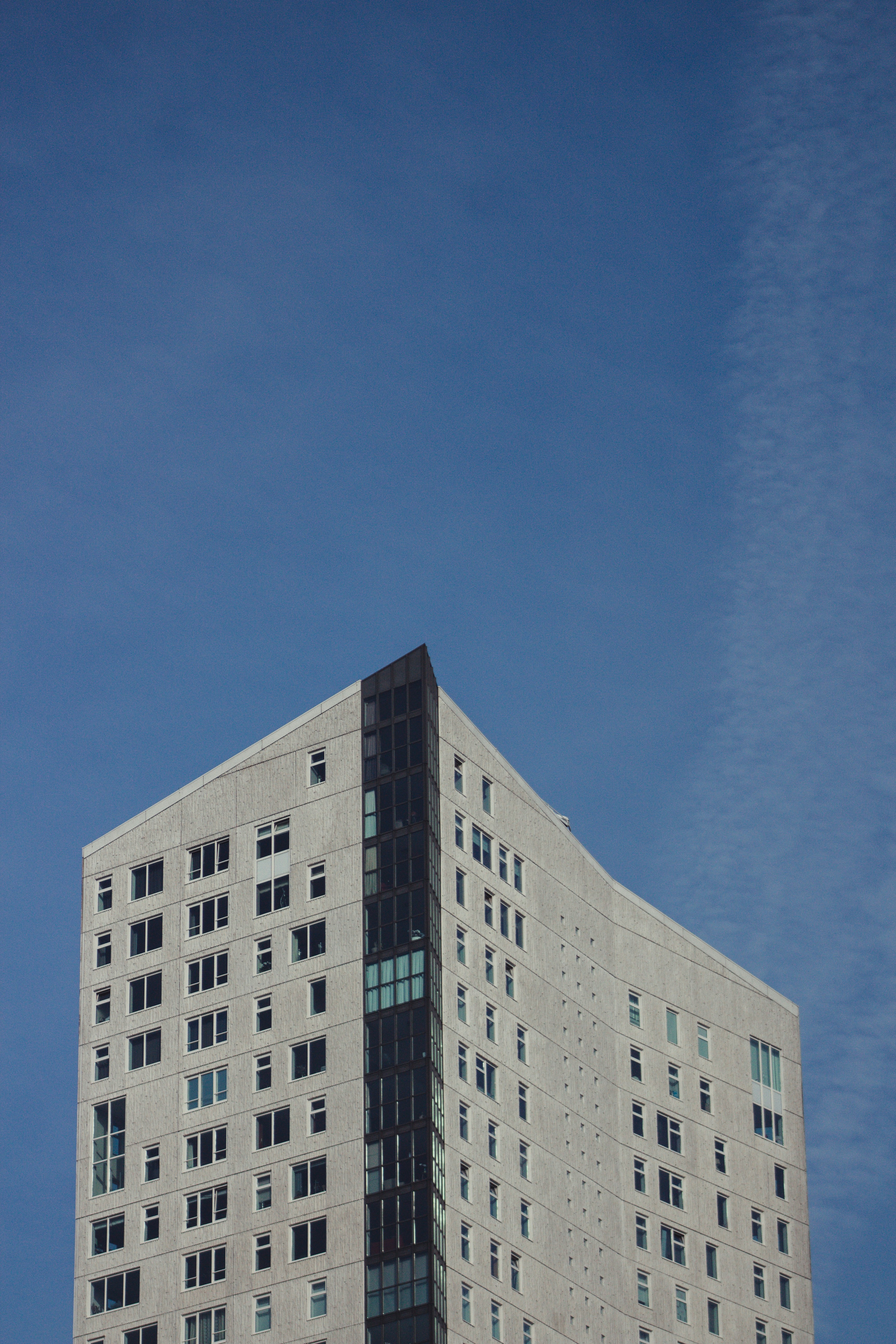 A contemporary high-rise building with a sleek facade, reaching toward a clear blue sky, showcasing modern design elements.
