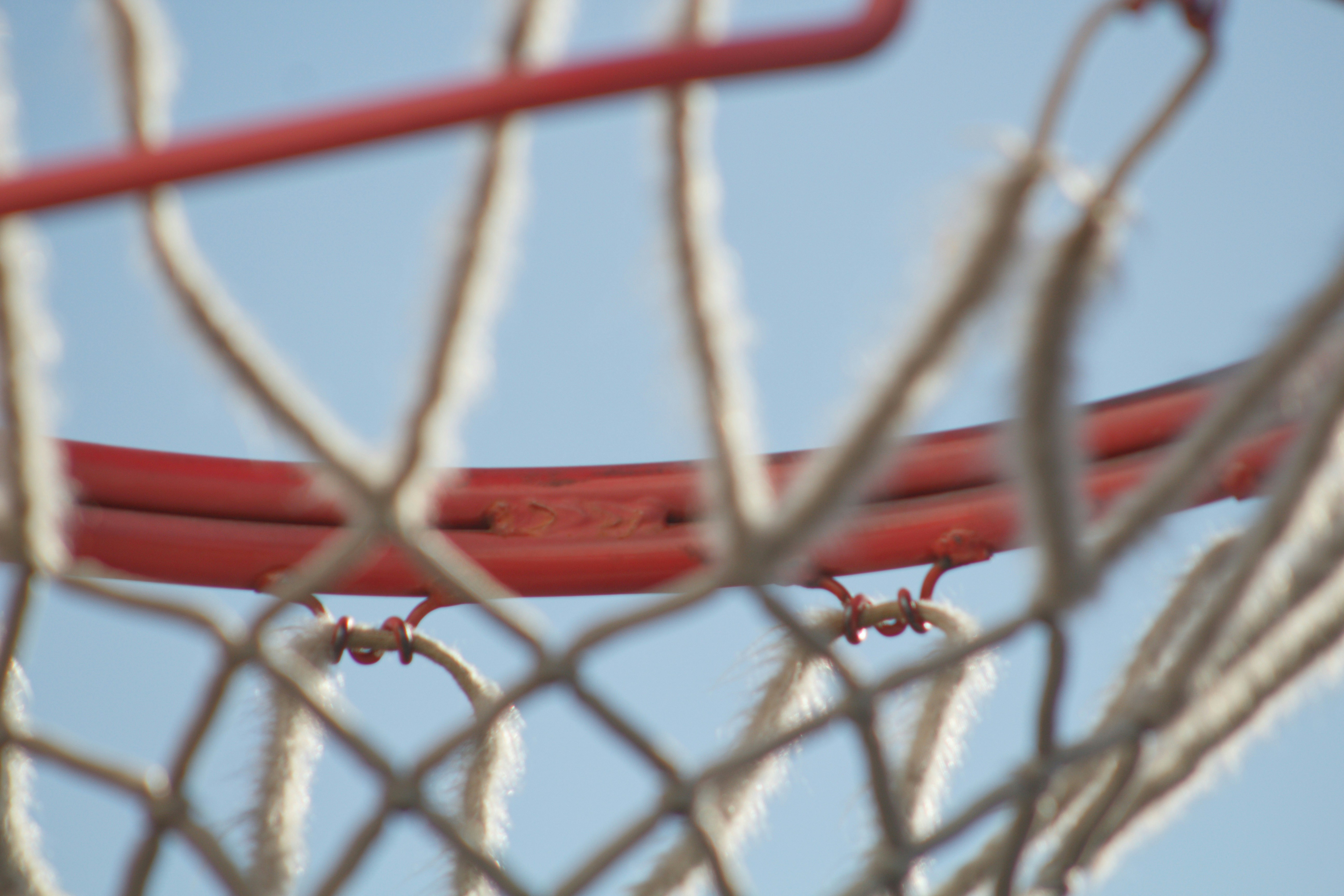 Threads in the Air: close-up of a goal net framed by red bars against a pale blue sky