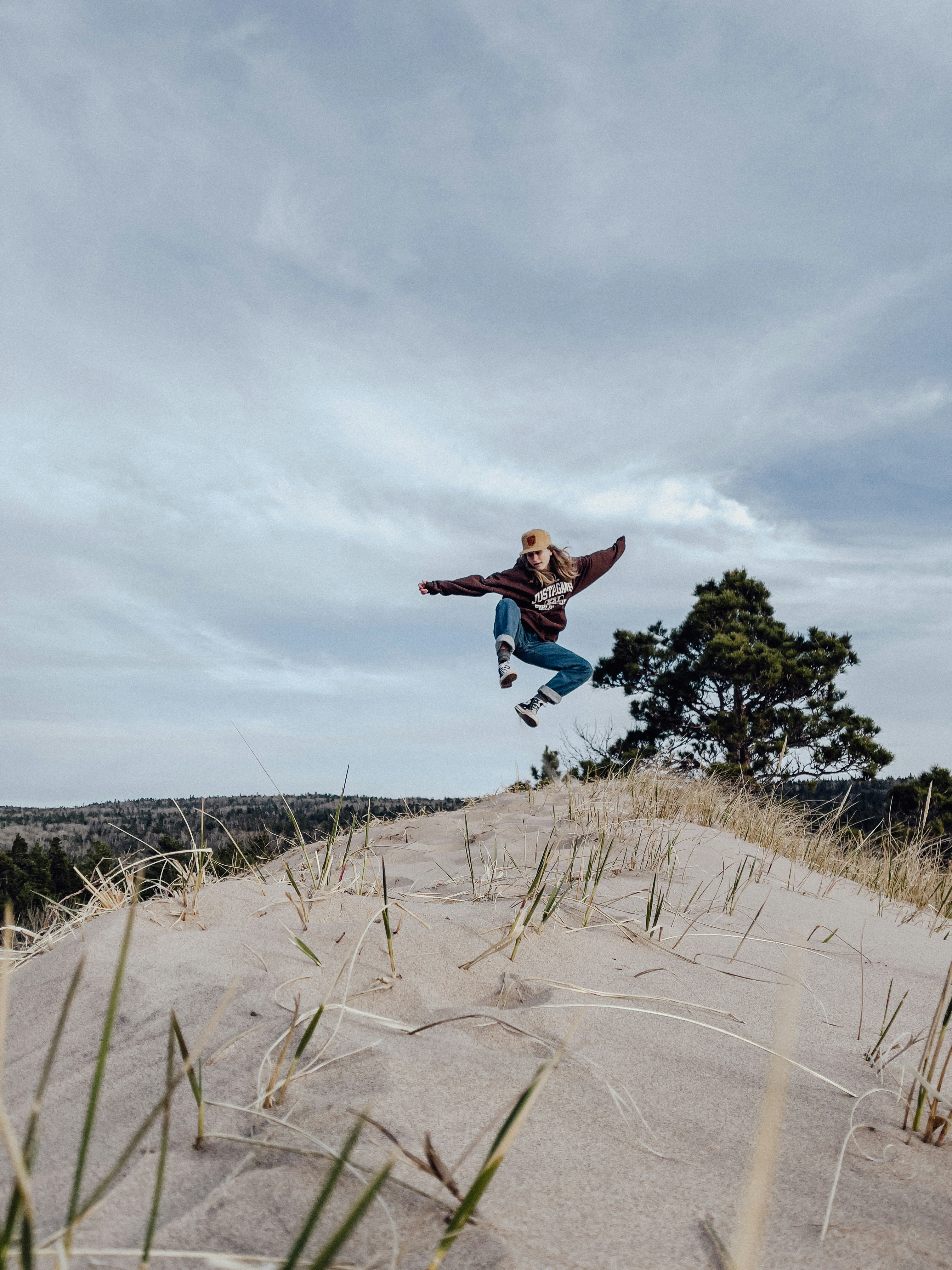 Midair on the Crest: A Youthful Leap Over a Sand Dune
