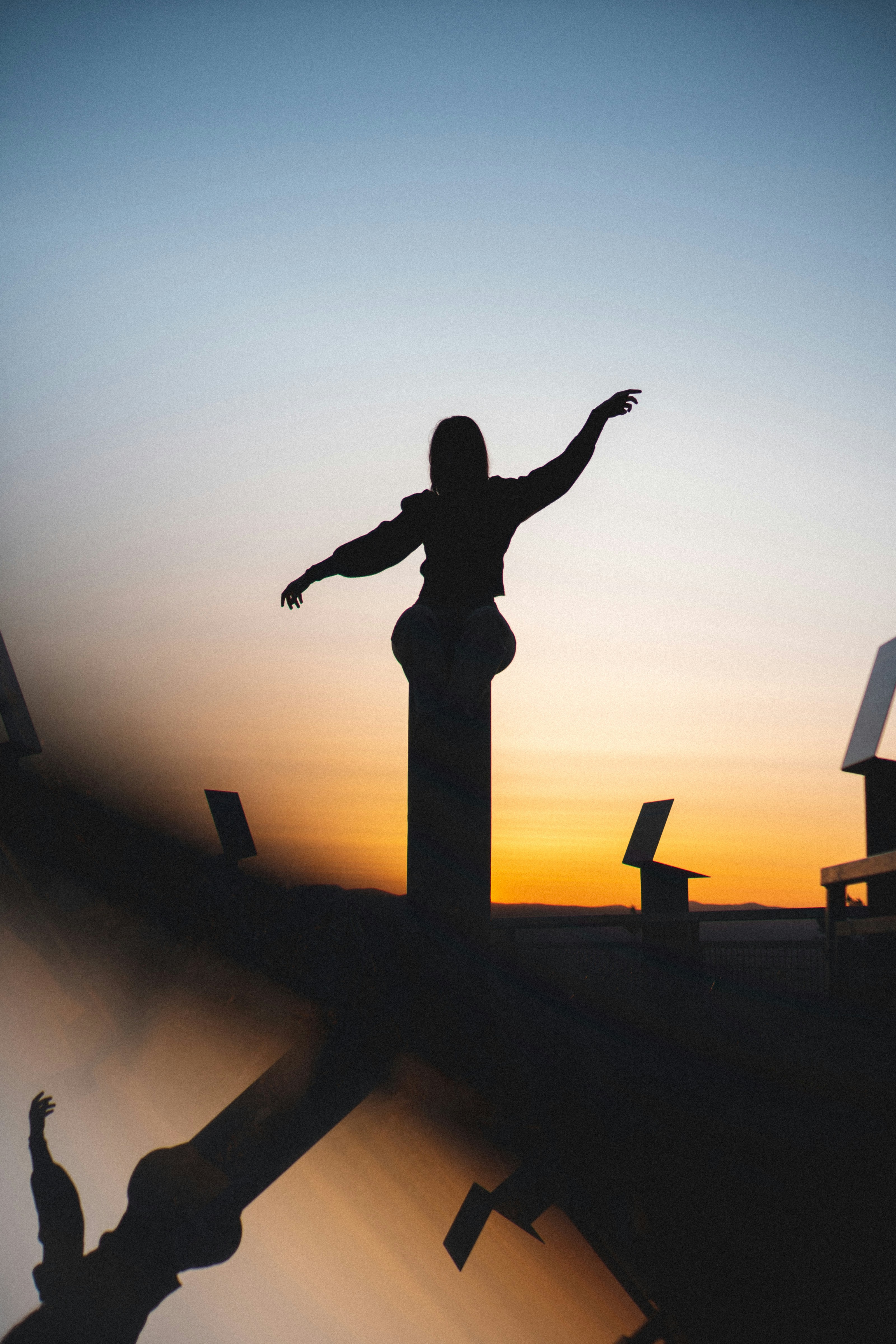 Silhouette of a dancer poised on a pedestal against a vibrant sunset backdrop, capturing a moment of grace and freedom.
