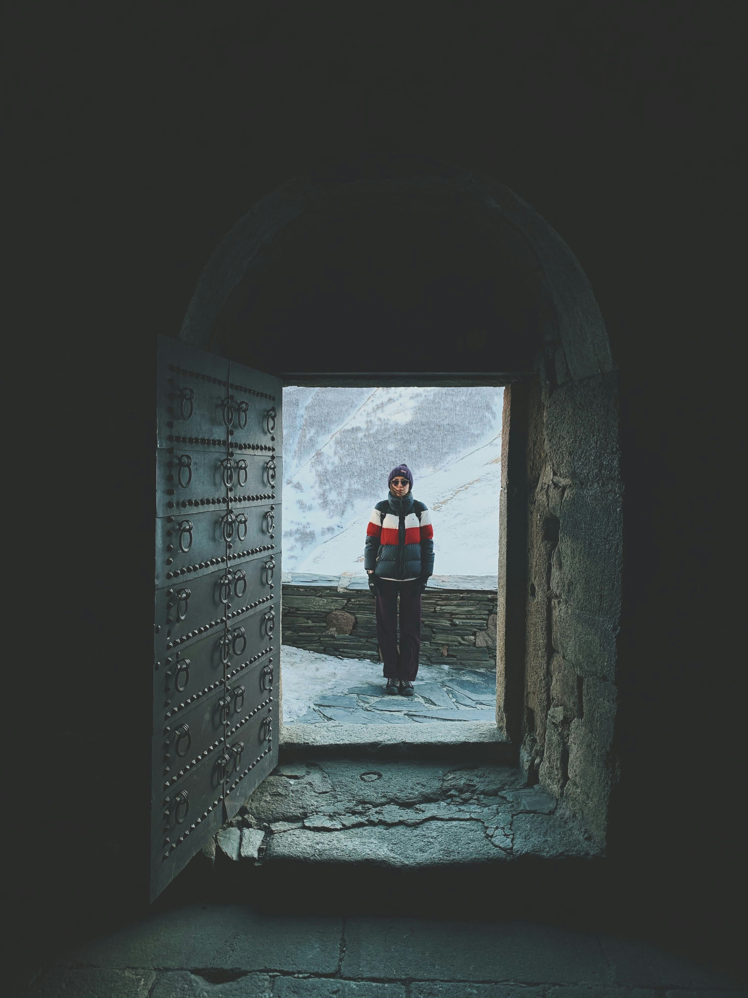 Gergetti Church, Kazbegi, GE | man in black jacket and black pants standing on tunnel
