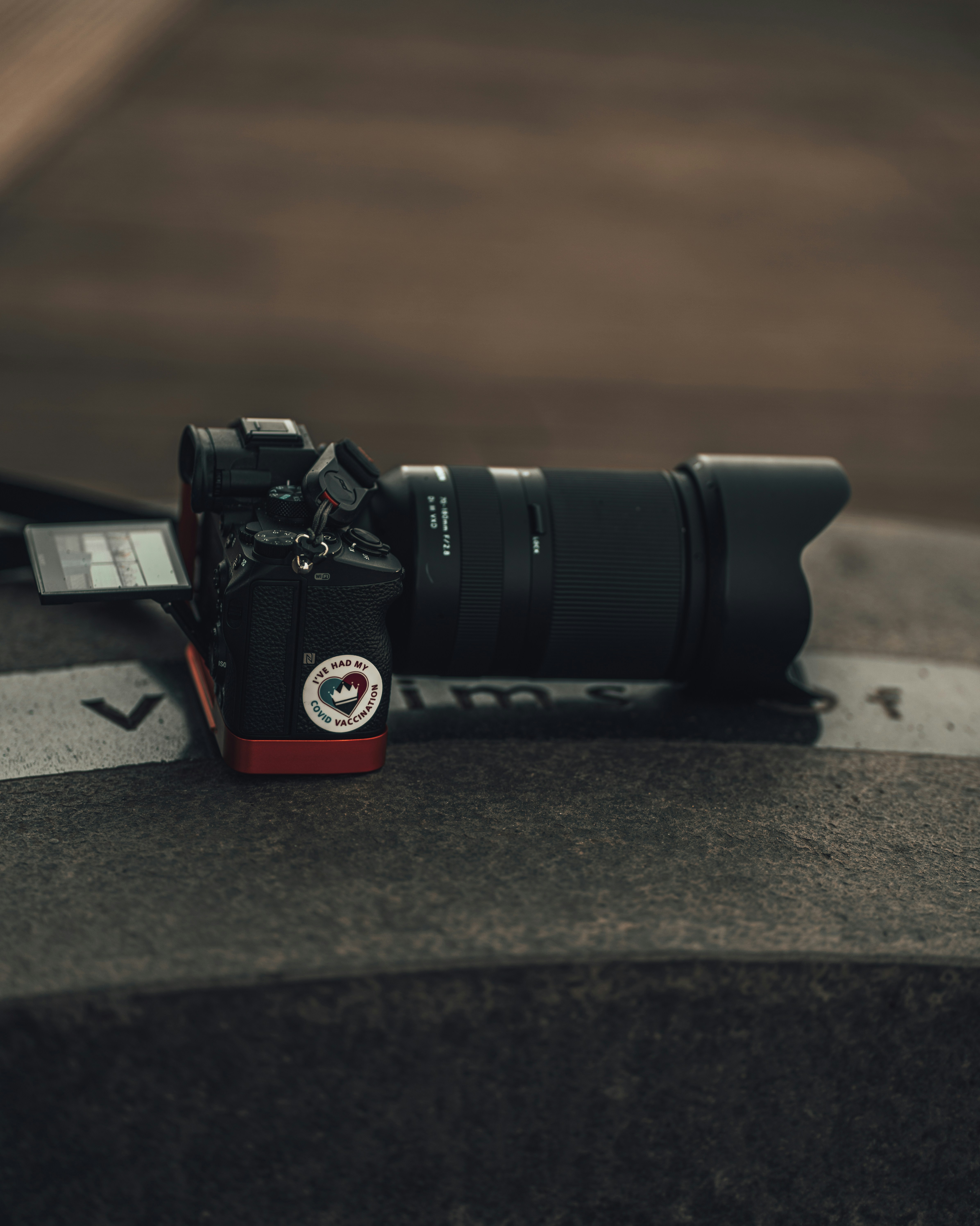 Red-Accented Pro Lens Resting on a Weathered Surface: A Quiet Portrait of a Mirrorless Rig