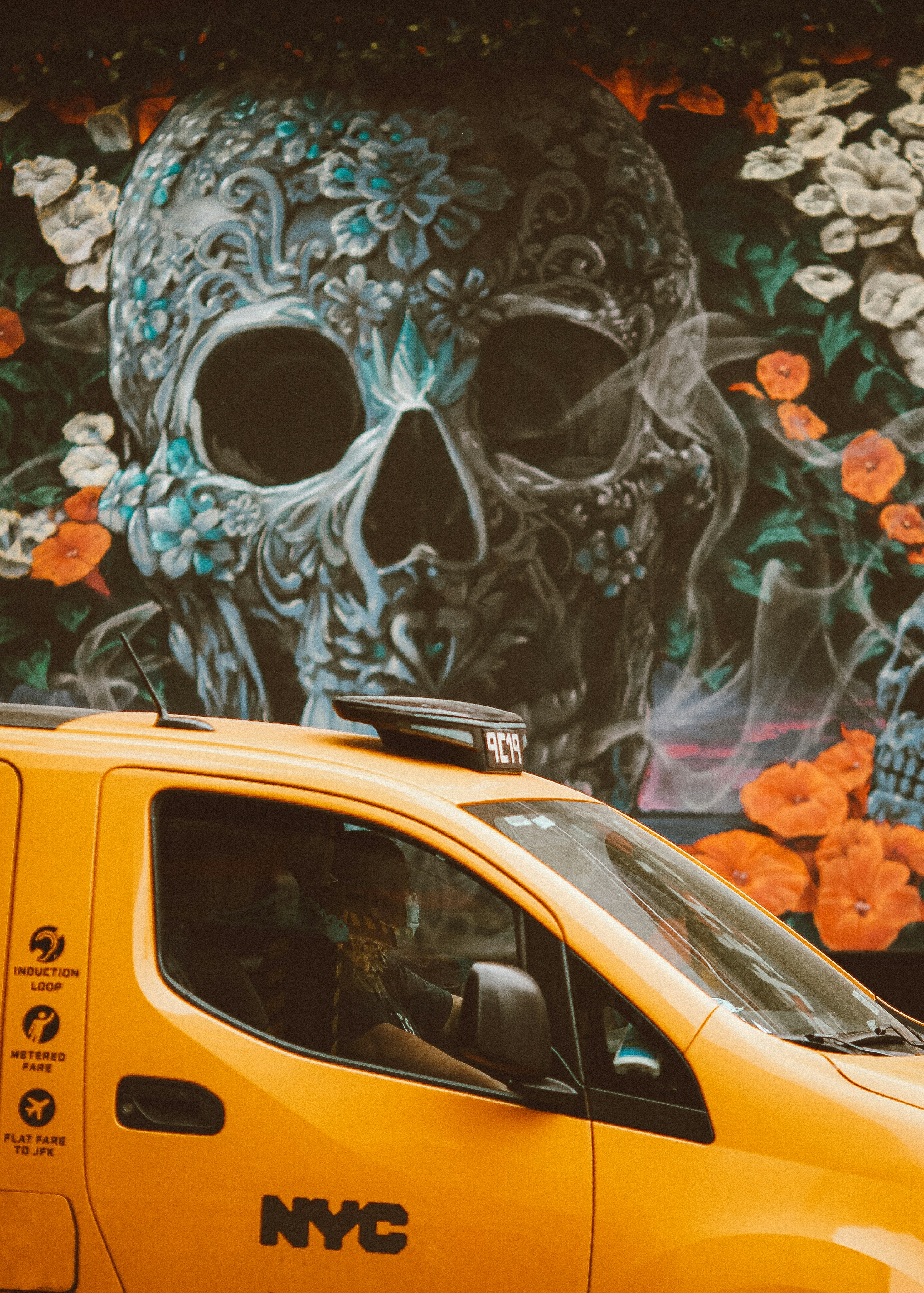 Yellow NYC Taxi Before a Floral Skull Mural Under Streetlight