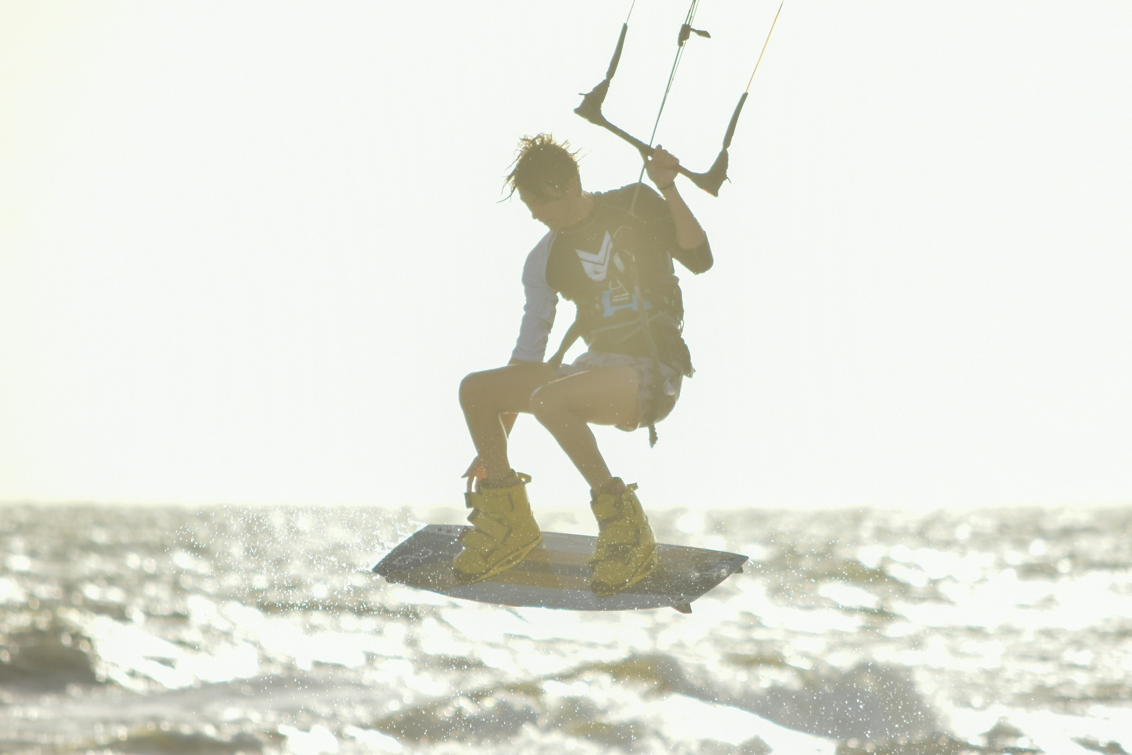 Glide and Grit: A Kite Surfer Hovering Above the Flicker of Waves