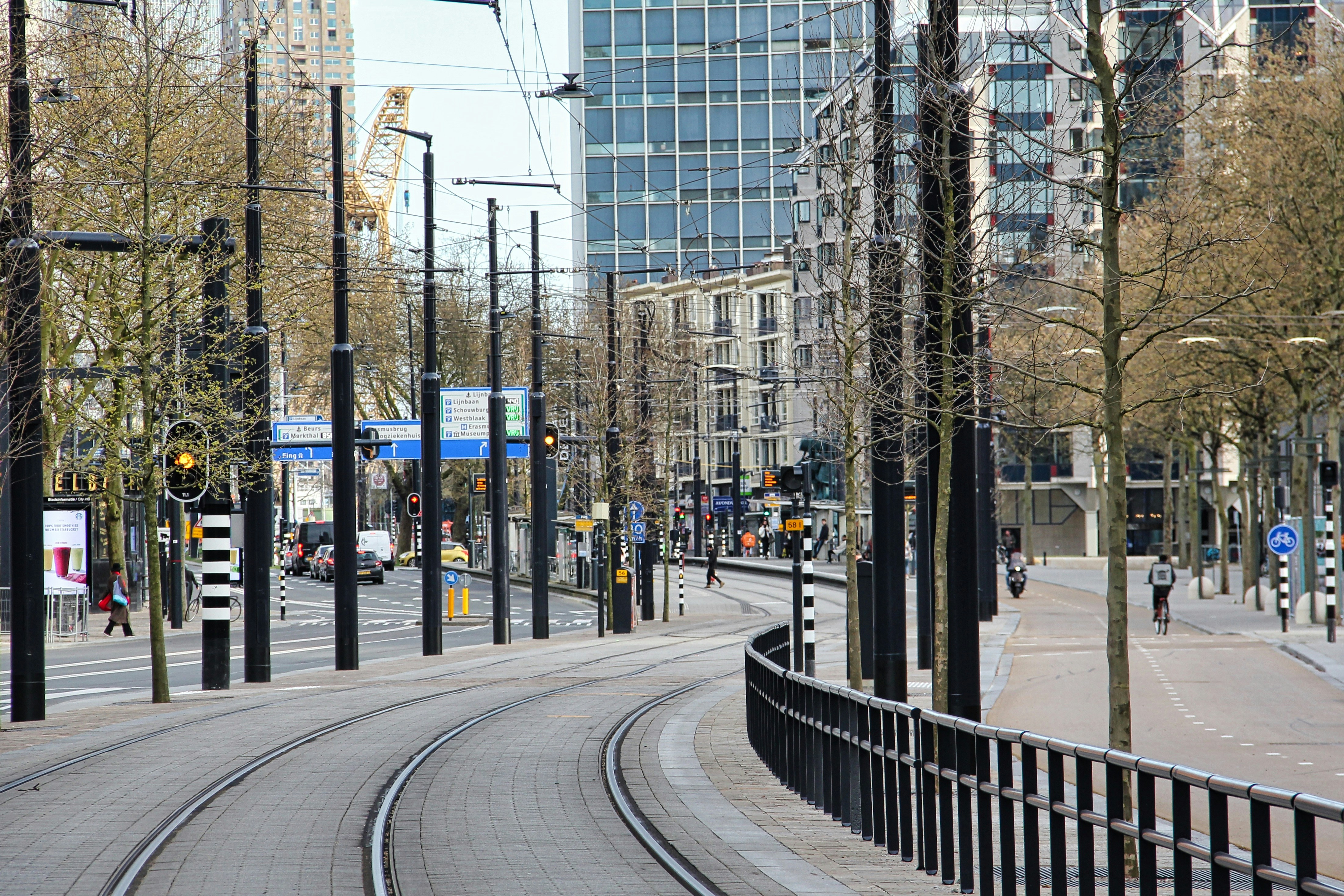 Tram tracks winding through a contemporary urban landscape, flanked by trees and modern buildings. The scene captures the essence of city life and transportation.