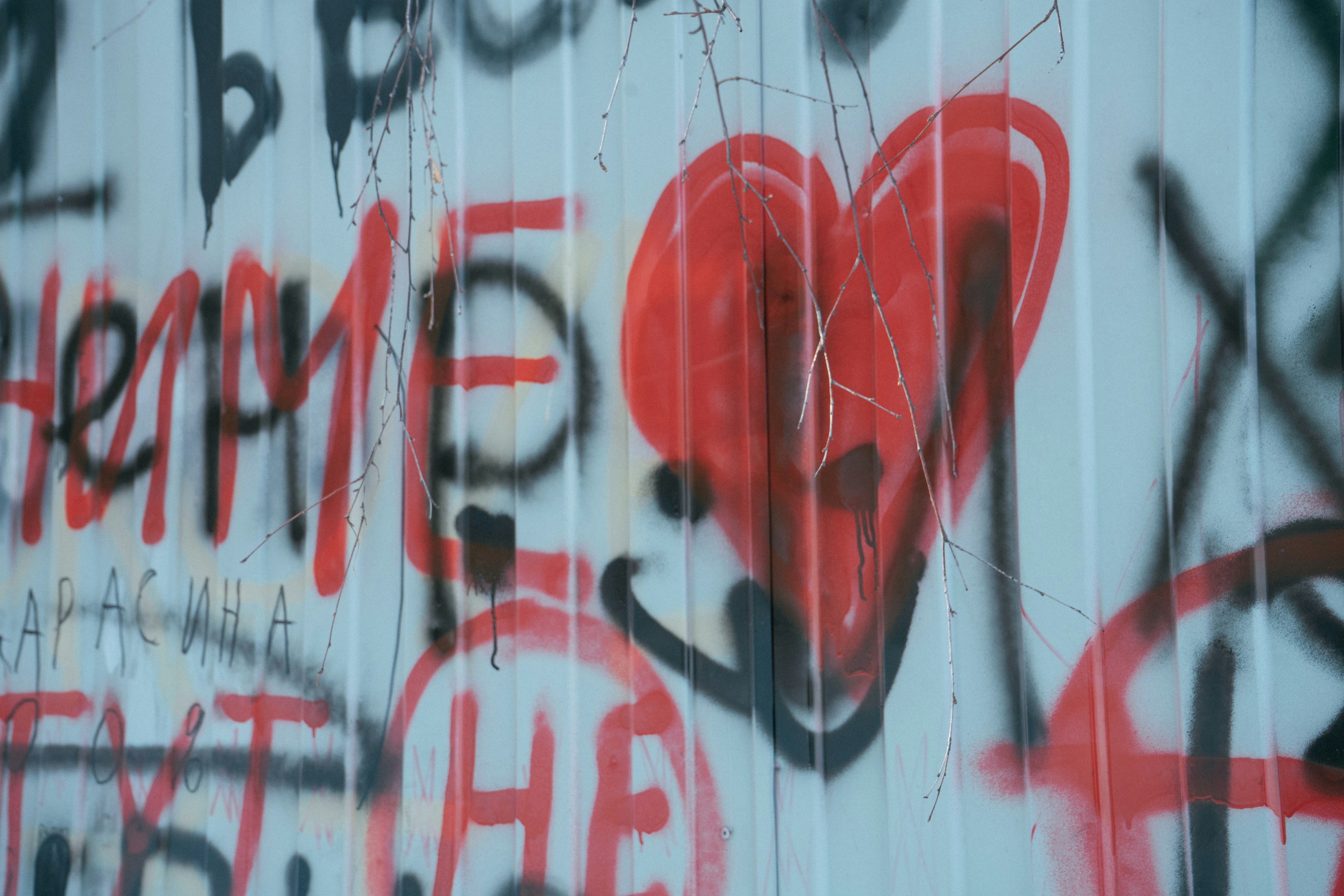 Colorful graffiti featuring a prominent red heart and bold text on a weathered metal surface. The artwork conveys a mix of emotions and urban culture.