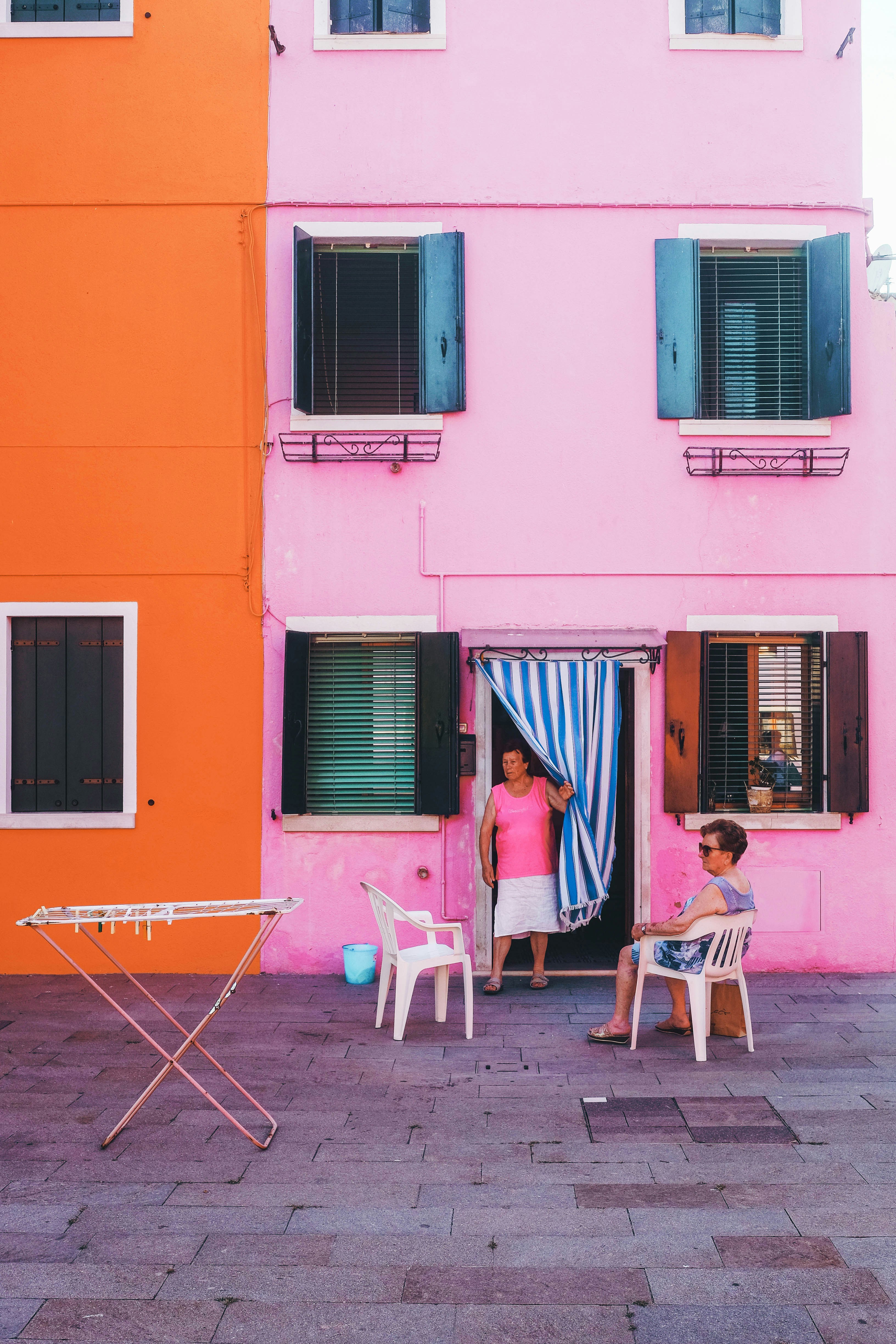 Bubblegum Pink Facade with Striped Curtain: A Quiet Color-Saturated Street Portrait