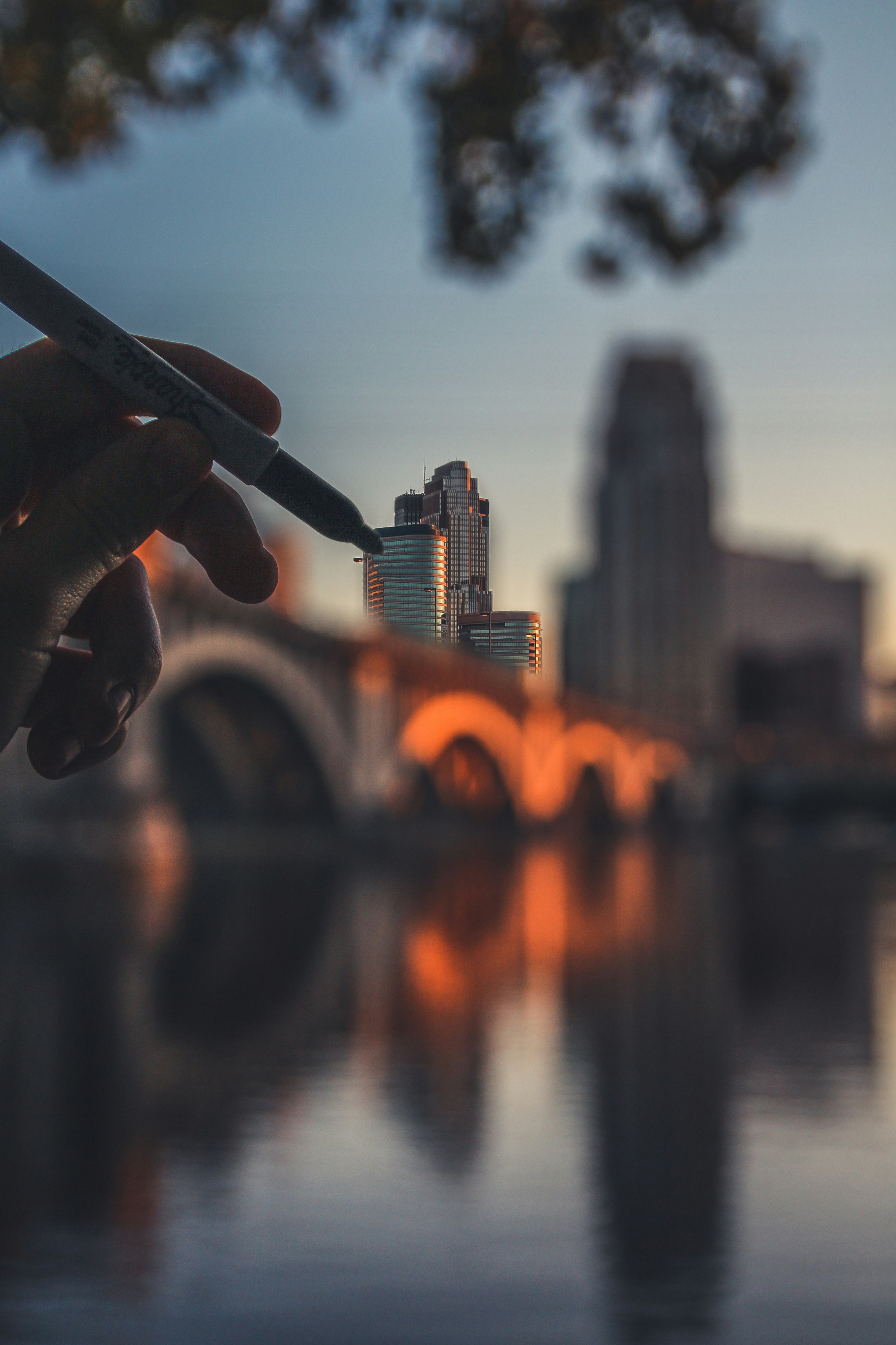 Marker in Focus: A Hand with a Marker Sketching the Skyline at Dusk