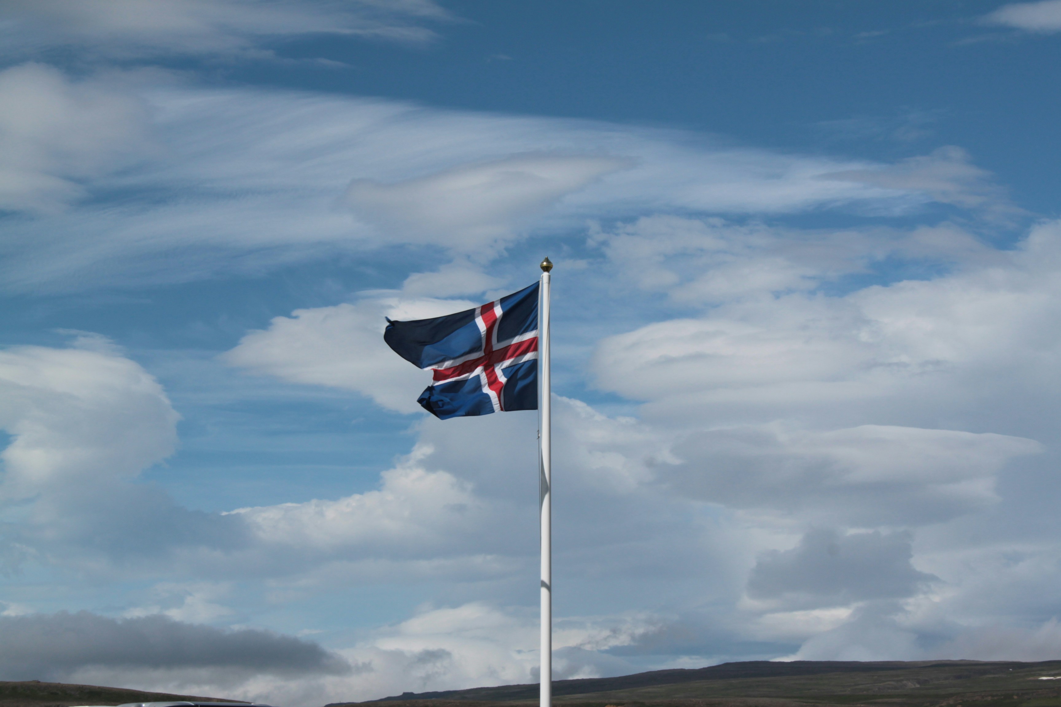 us a flag on pole under white clouds and blue sky during daytime
