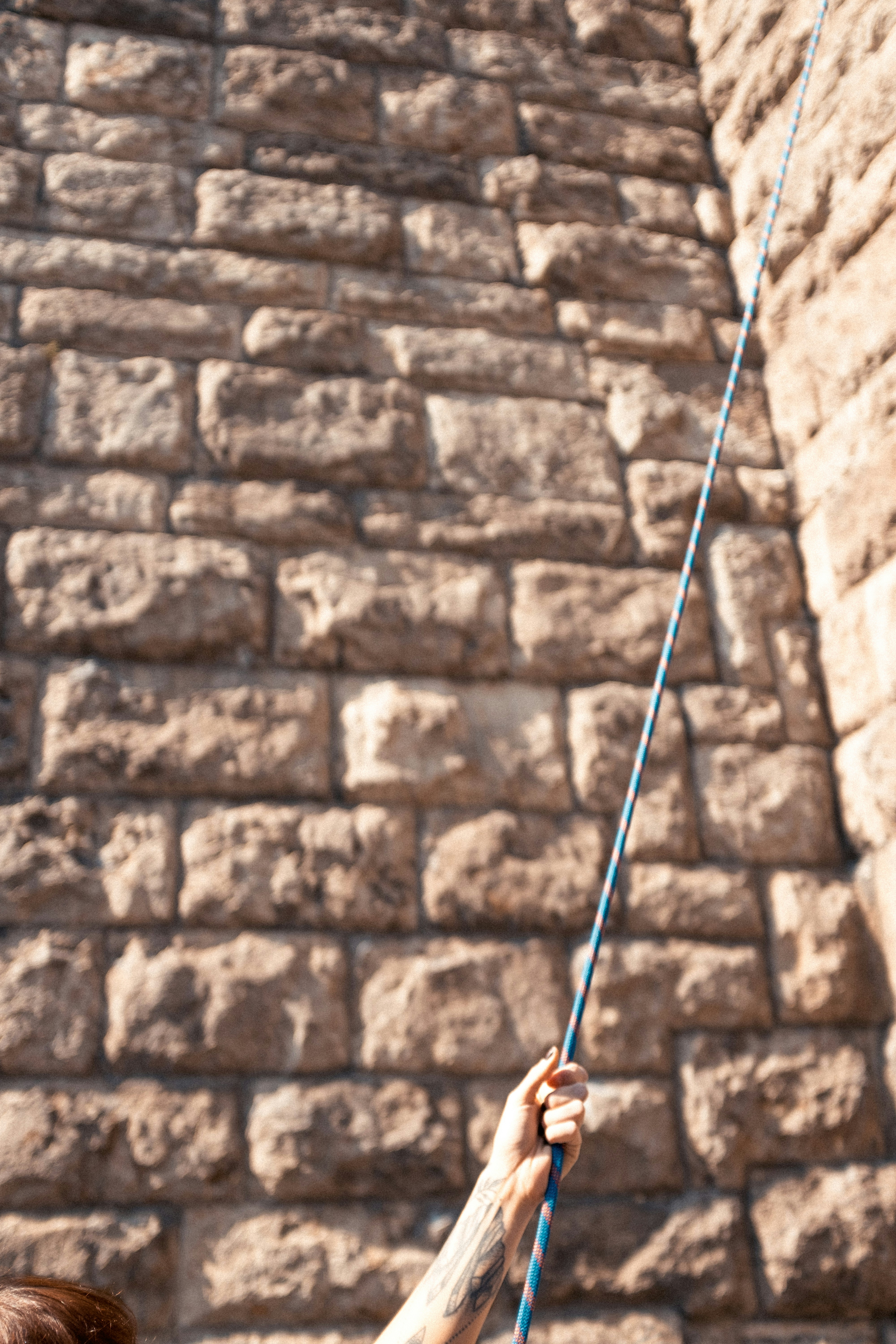 Rope and Reach: A Climber's Hand Draws the Line Up a Stone Wall