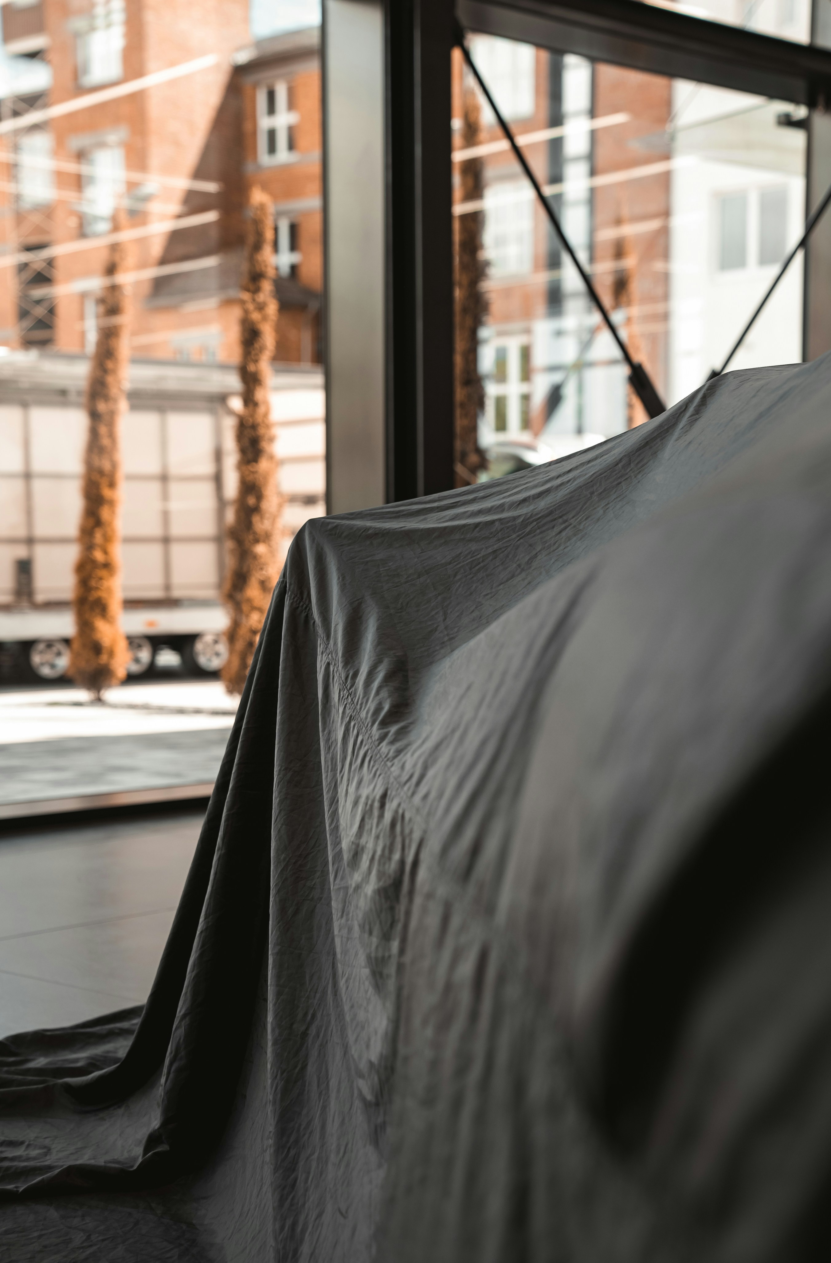 Shrouded Exhibit: A Draped Form against Industrial Glass and Brick