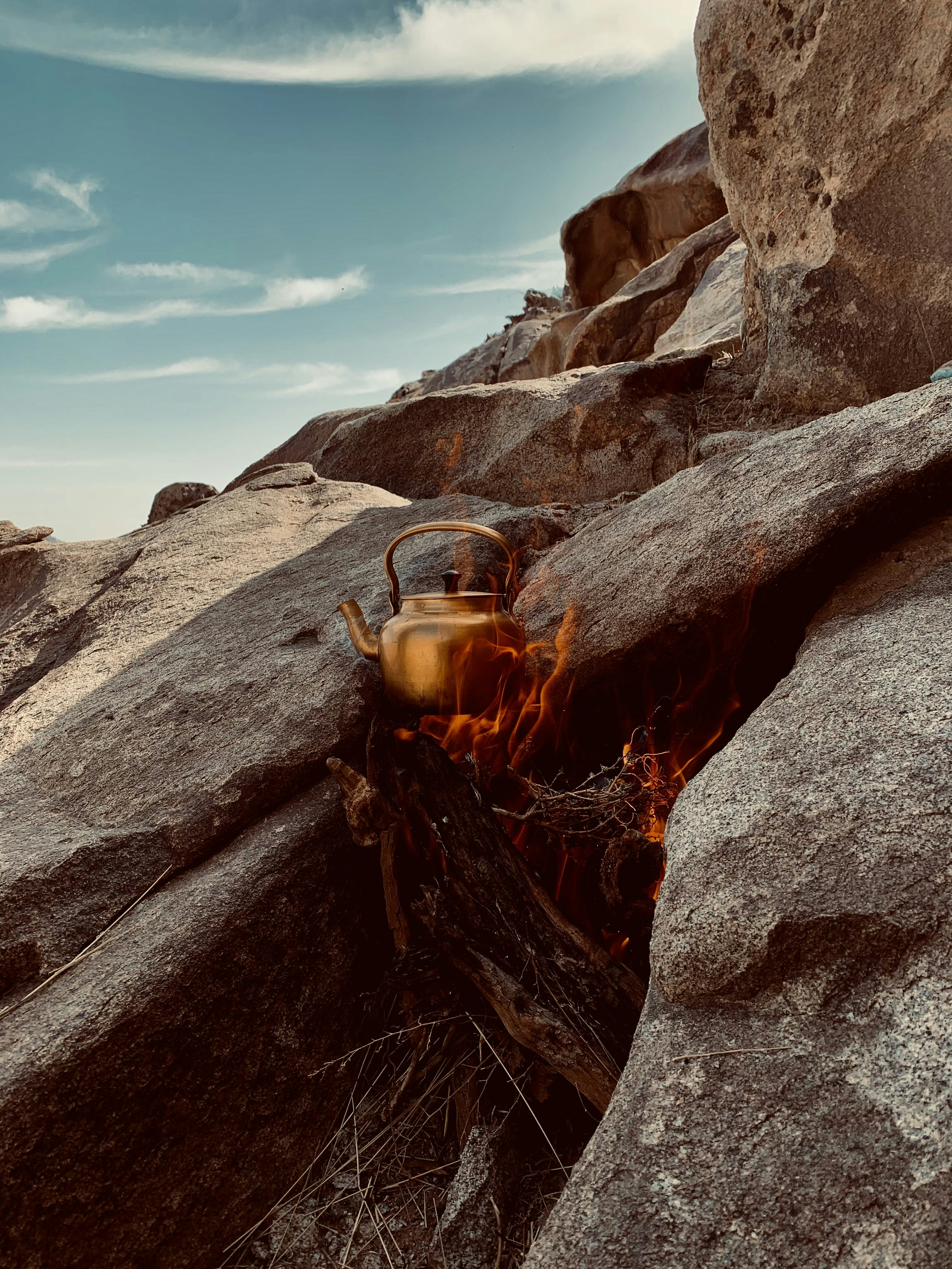 Boiling kettle between ancient rocks: a rogue flame amid a sunlit ascent
