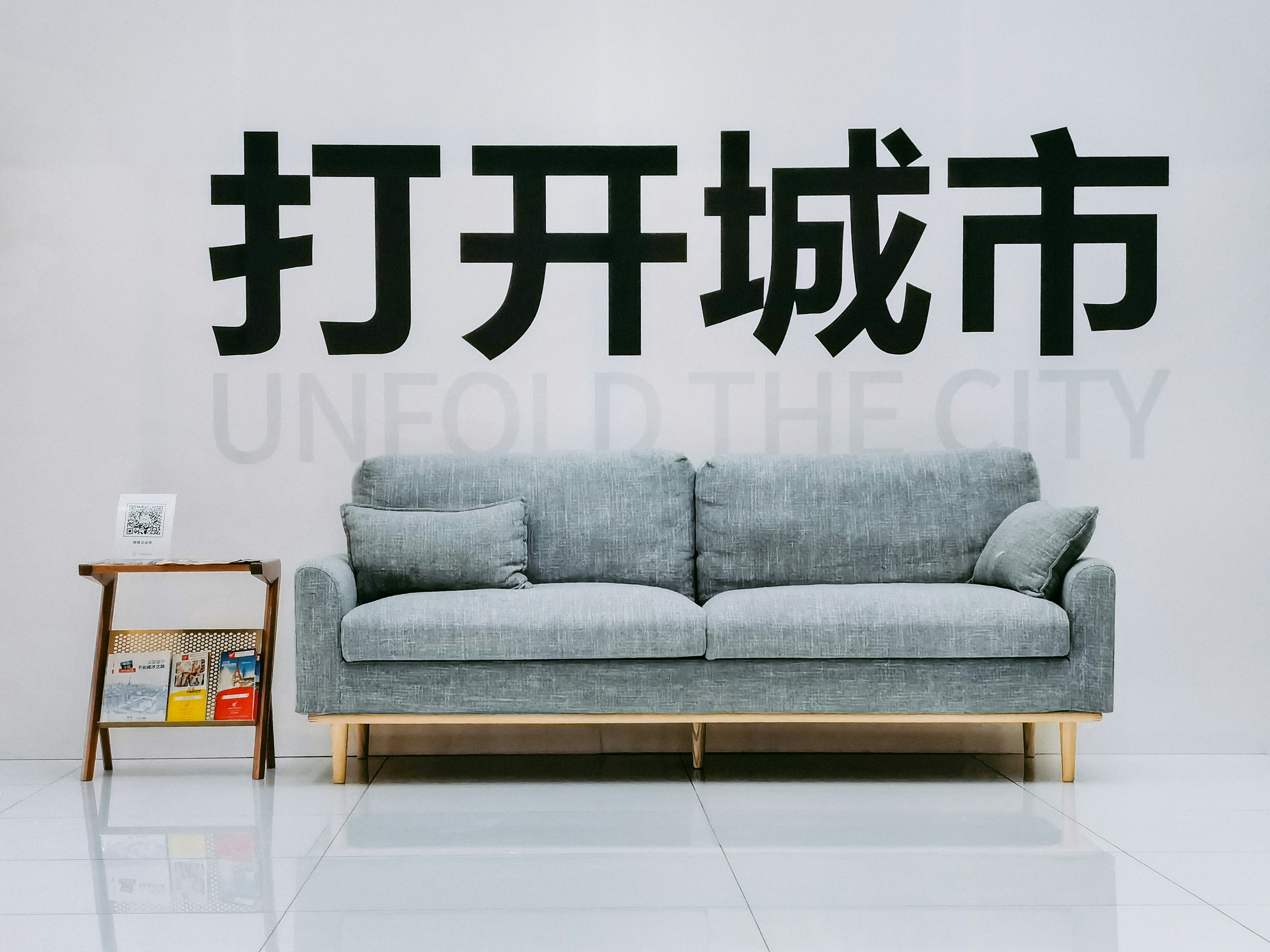 Minimalist interior featuring a gray sofa against a backdrop of bold typography, promoting urban exploration.