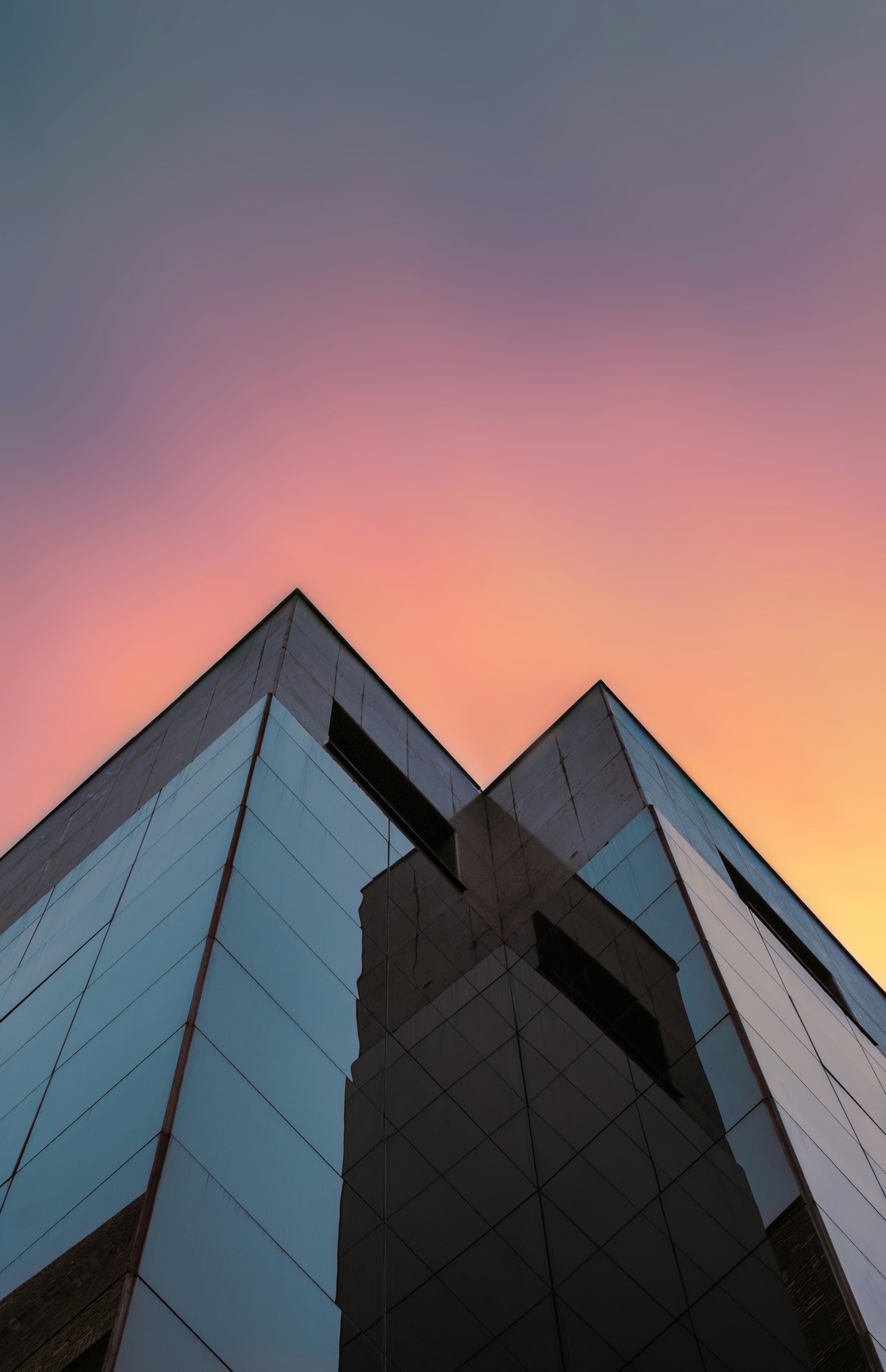 Glass and steel building facade reflecting a vibrant sunset sky.