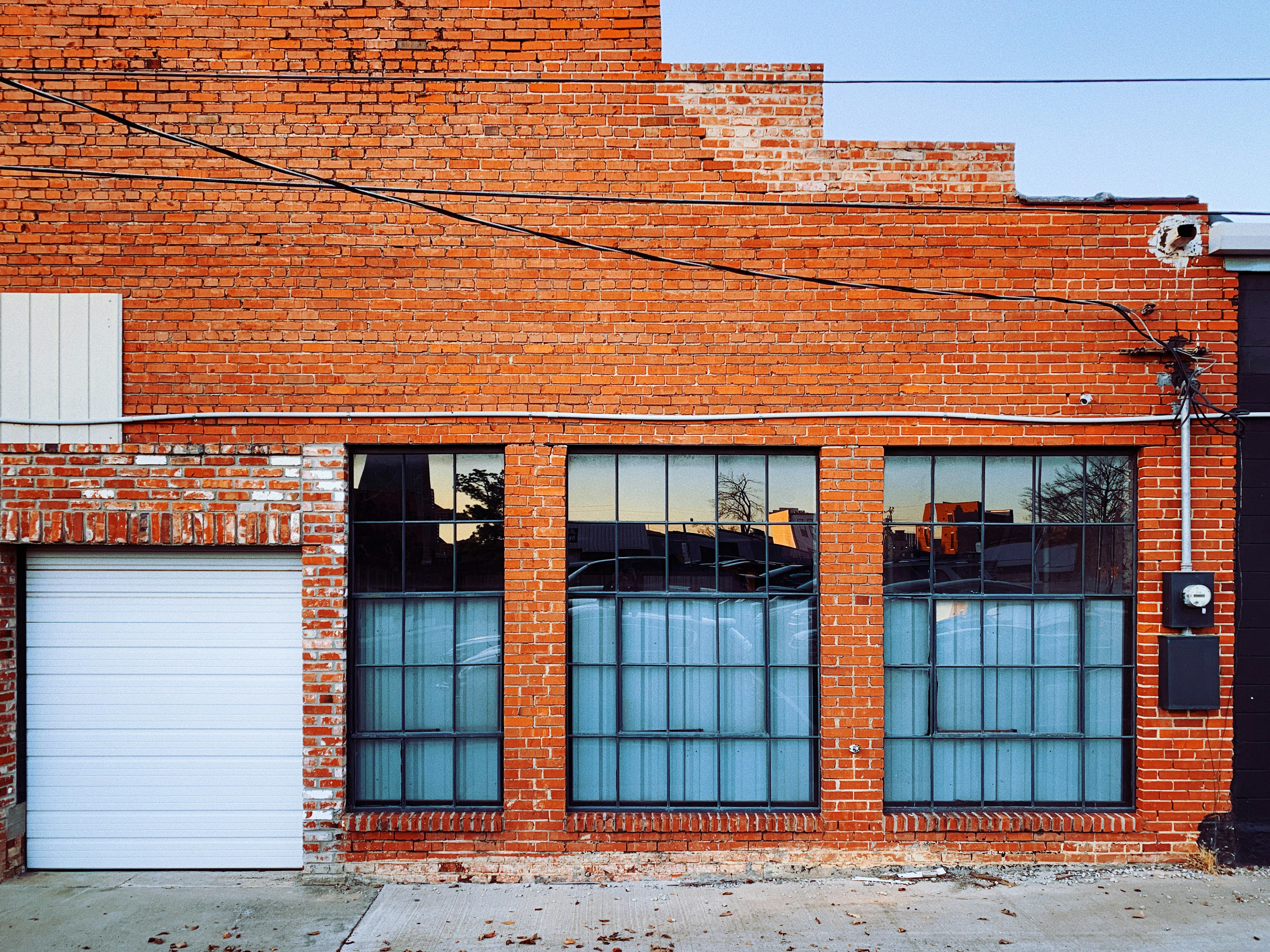 Red brick building with large glass windows and a white garage door.