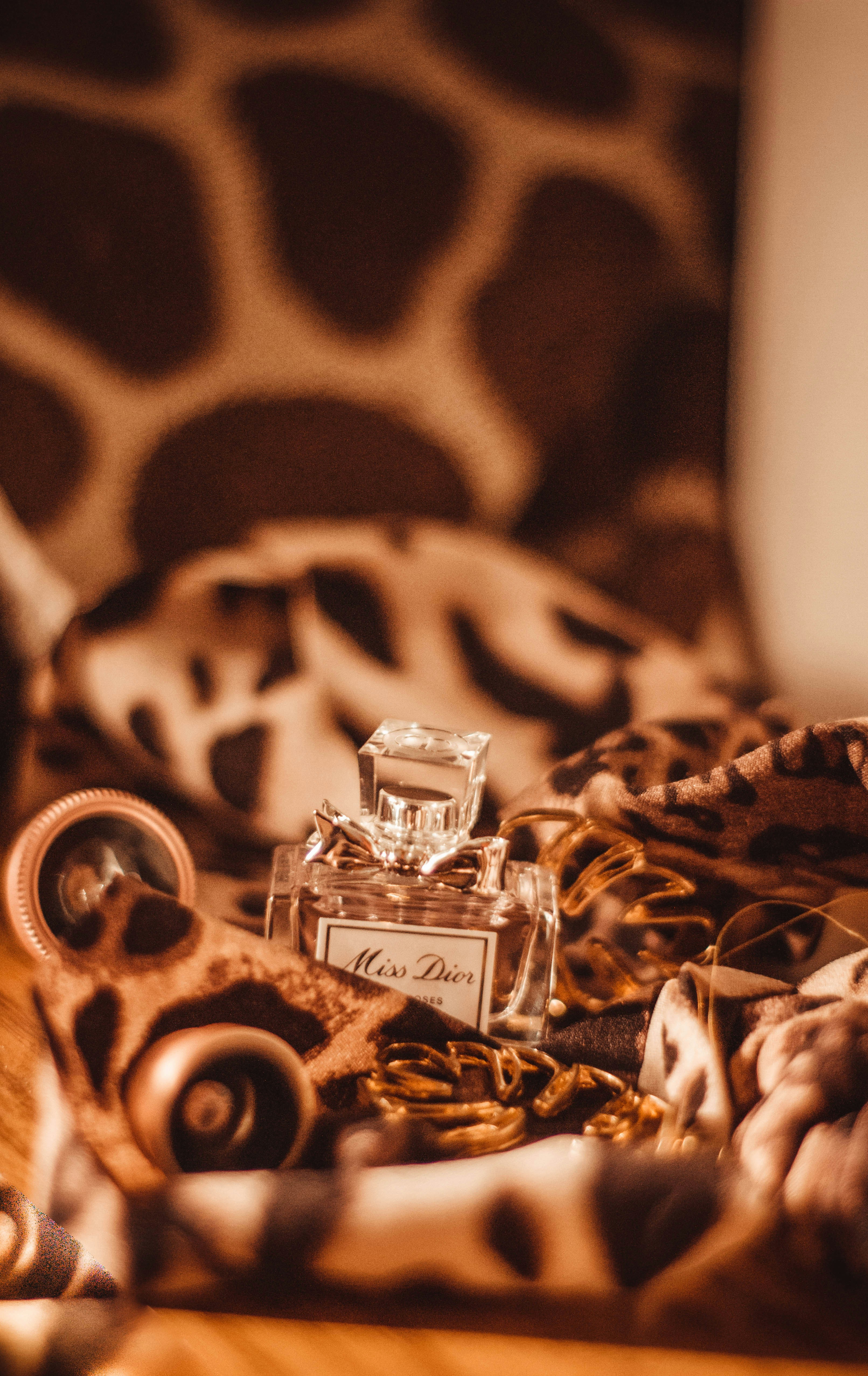 clear glass perfume bottle on brown and black textile