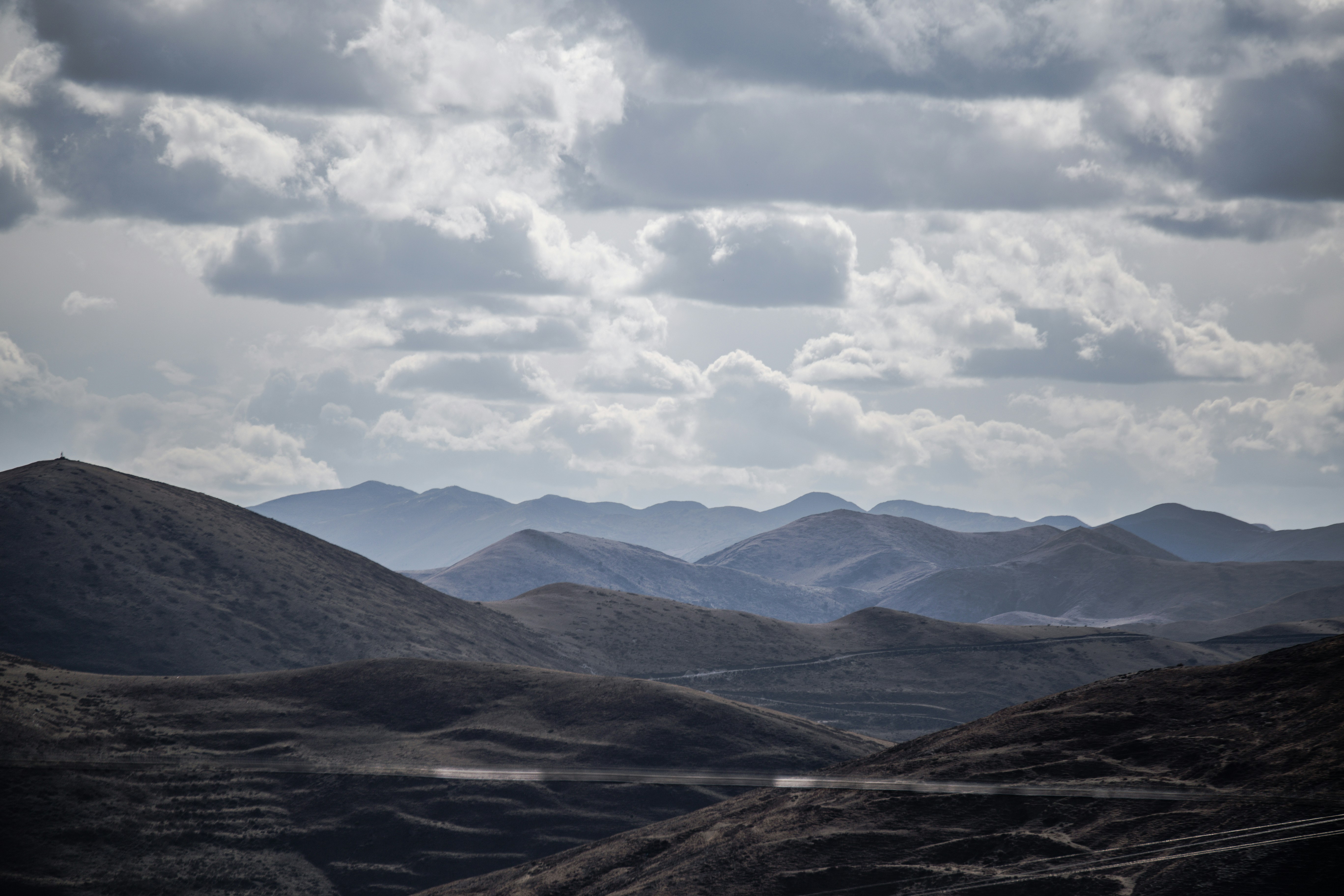 Layered mountain ranges under a cloudy sky, showcasing the subtle interplay of light and shadow in a remote landscape.