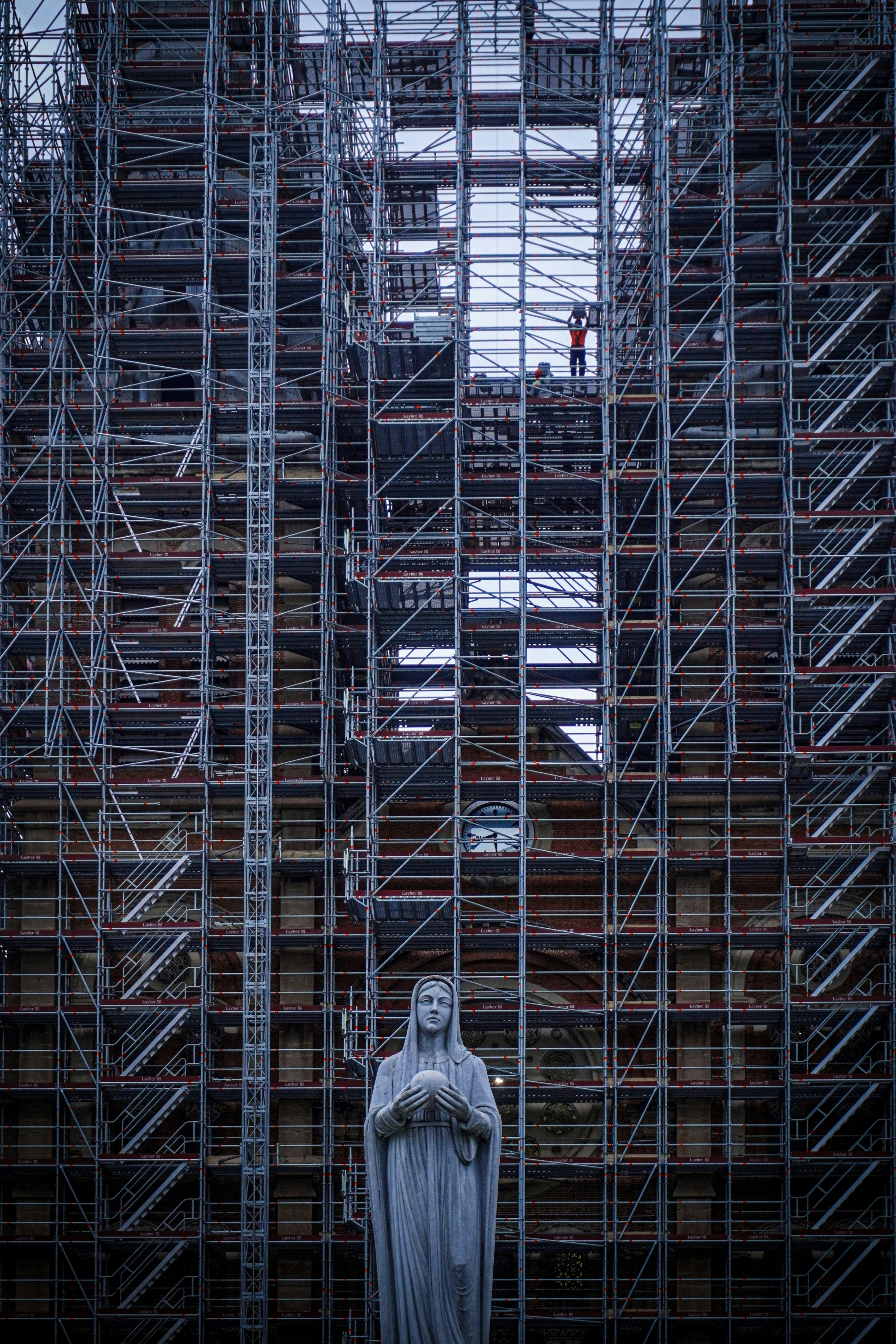 Foto Hombre con capucha gris parado en un marco de metal marrón ...