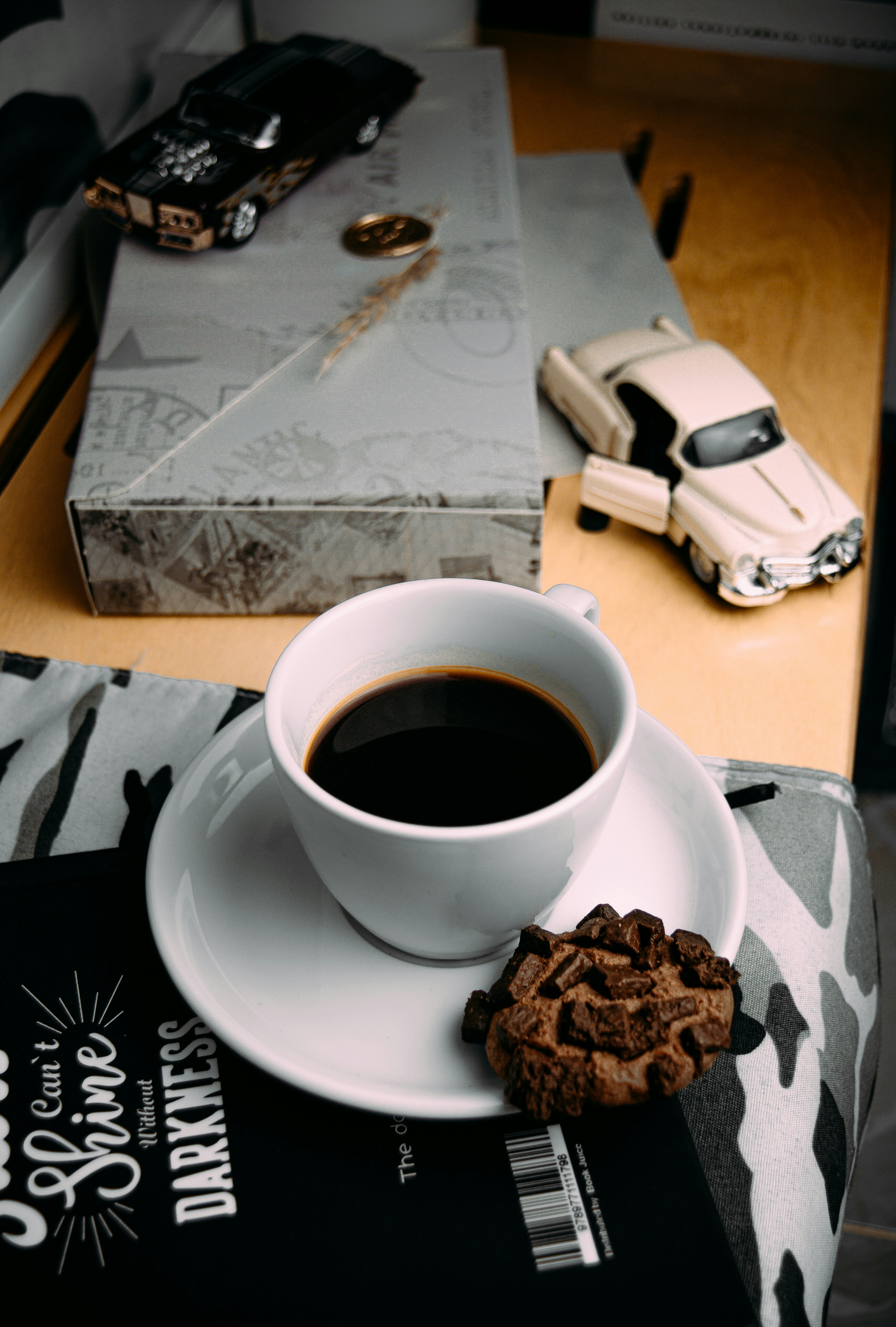 white coffee cup and chocolate cookie on black note with model toy cars and decoration frames