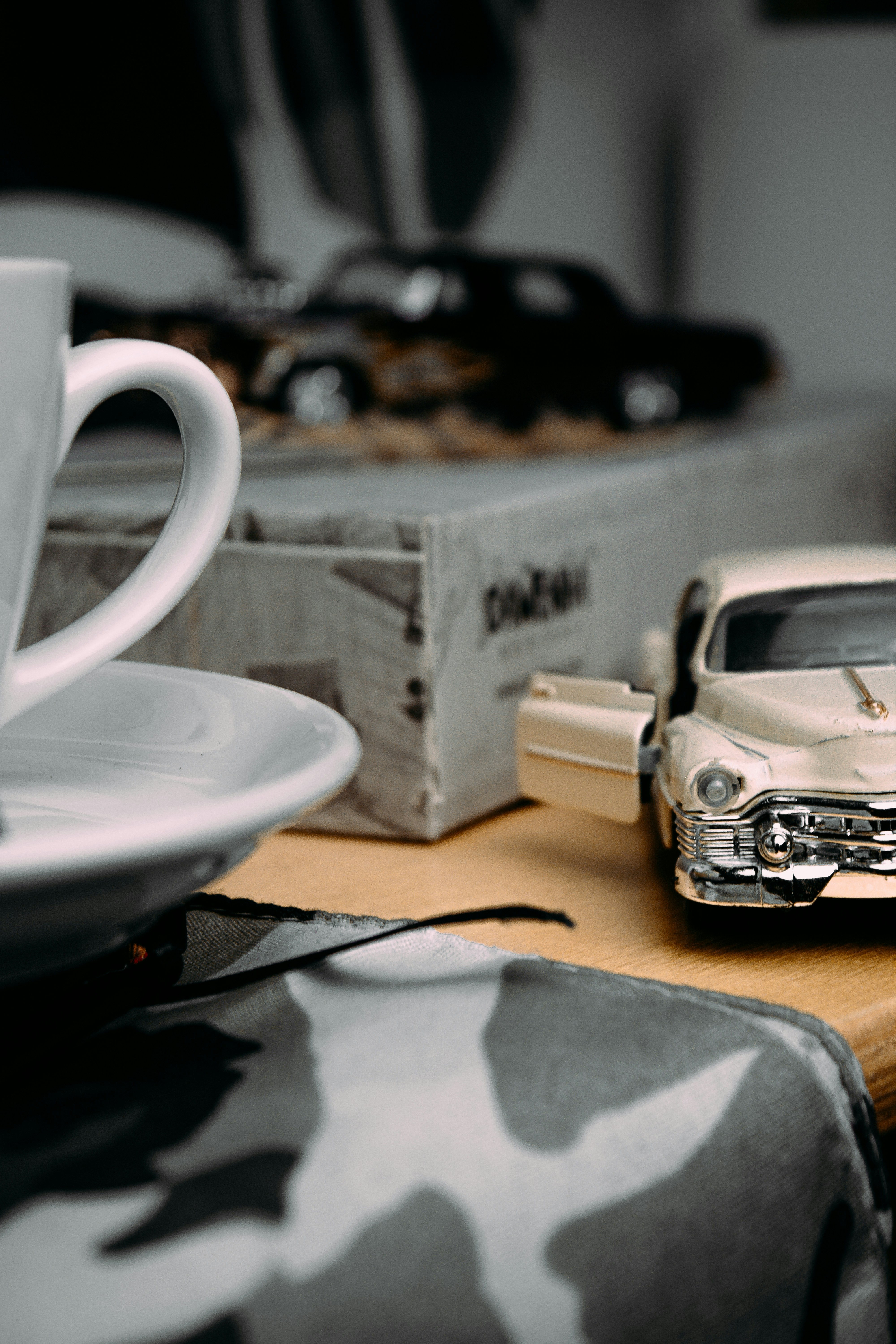 white coffee cup and chocolate cookie on black note with model toy cars and decoration frames