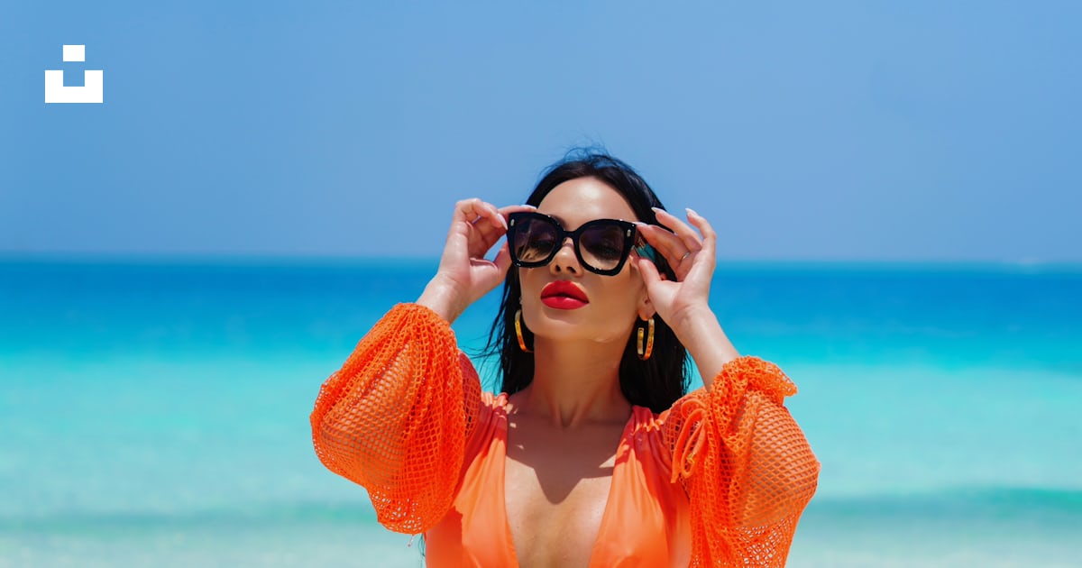 Woman In Orange One Piece Swimsuit Sitting On Beach Shore During