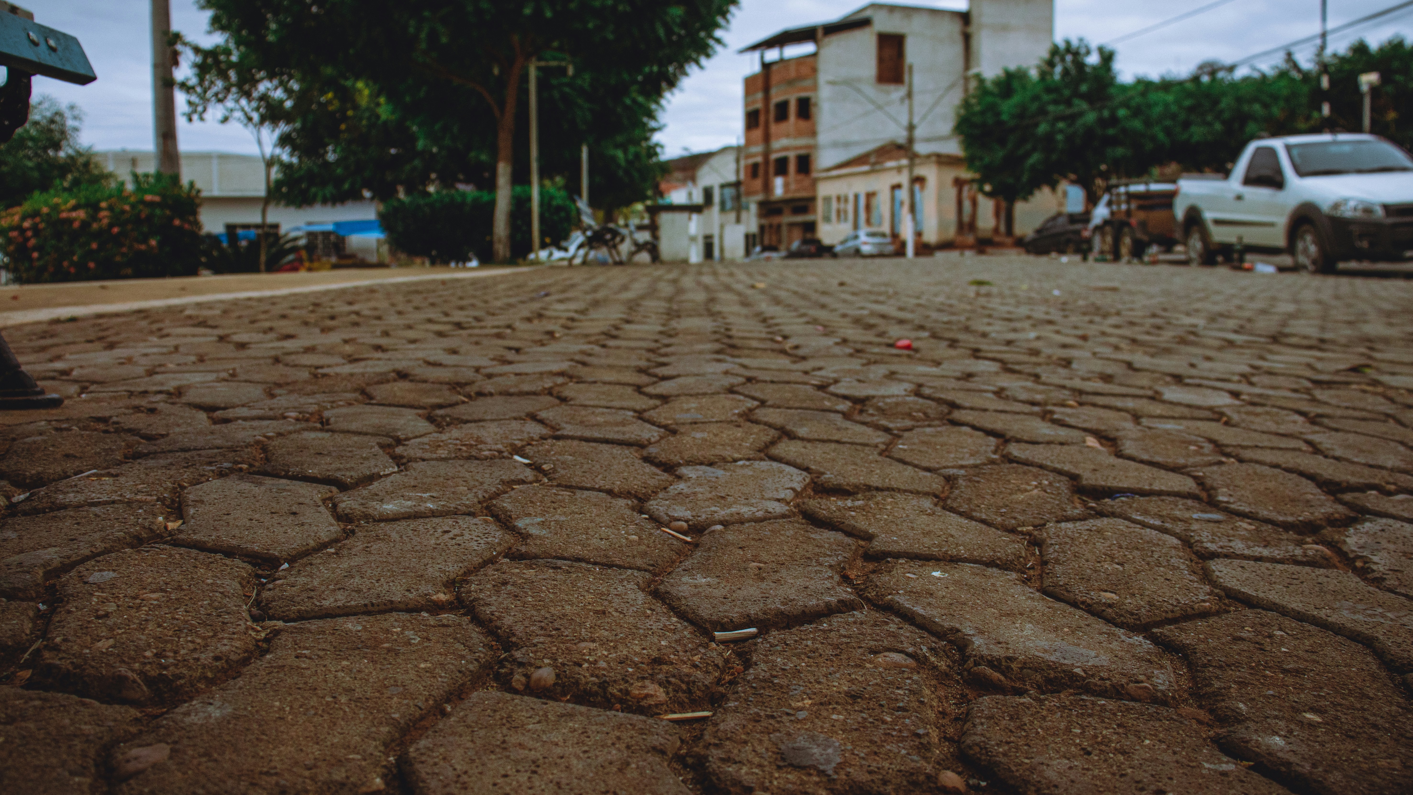 Hexagonal stone pavement leading into a bustling urban scene with buildings and greenery in the background.