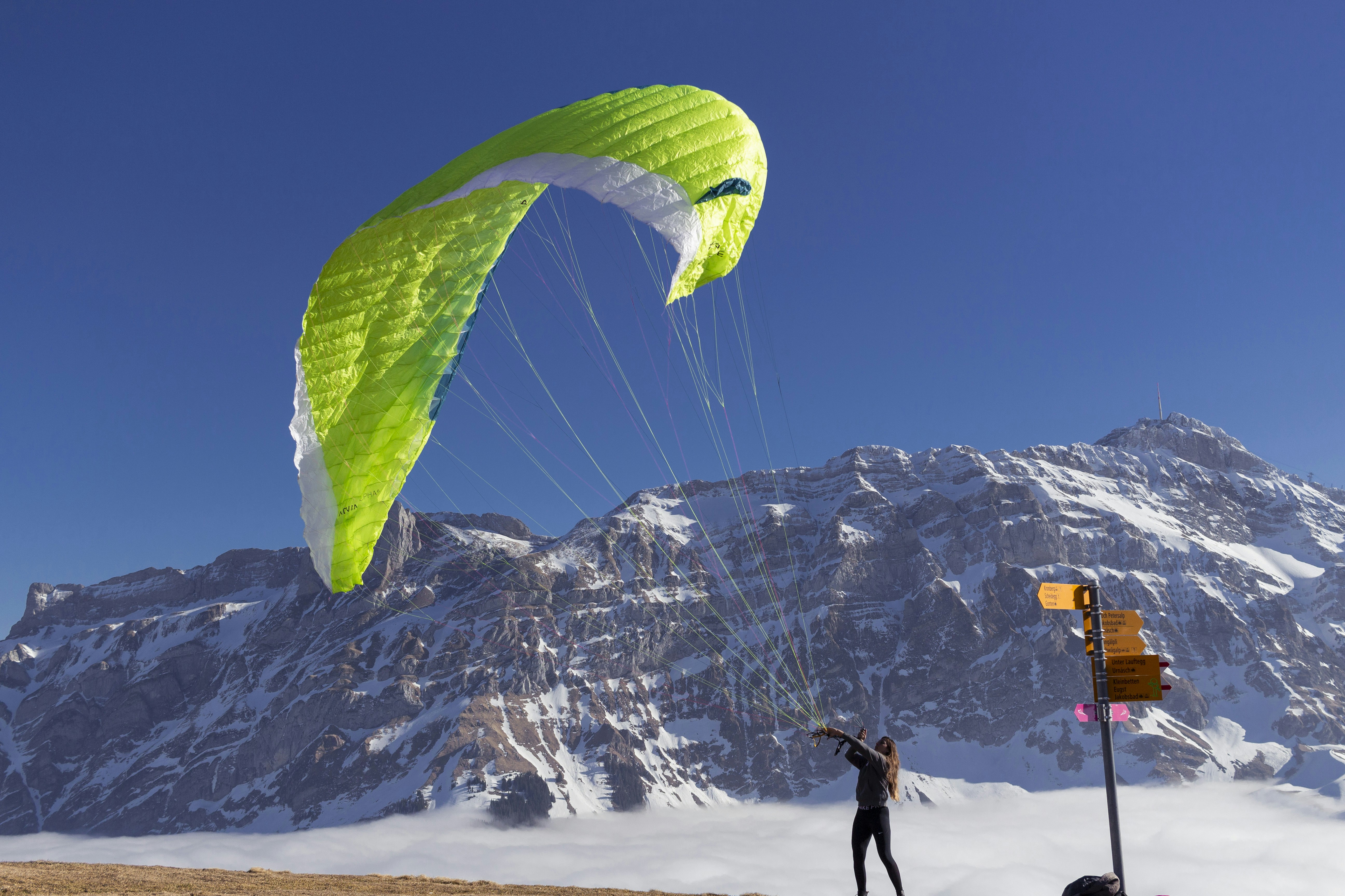 Lime-Green Paraglider Carves an Arc Across Sunlit Alpine Peaks