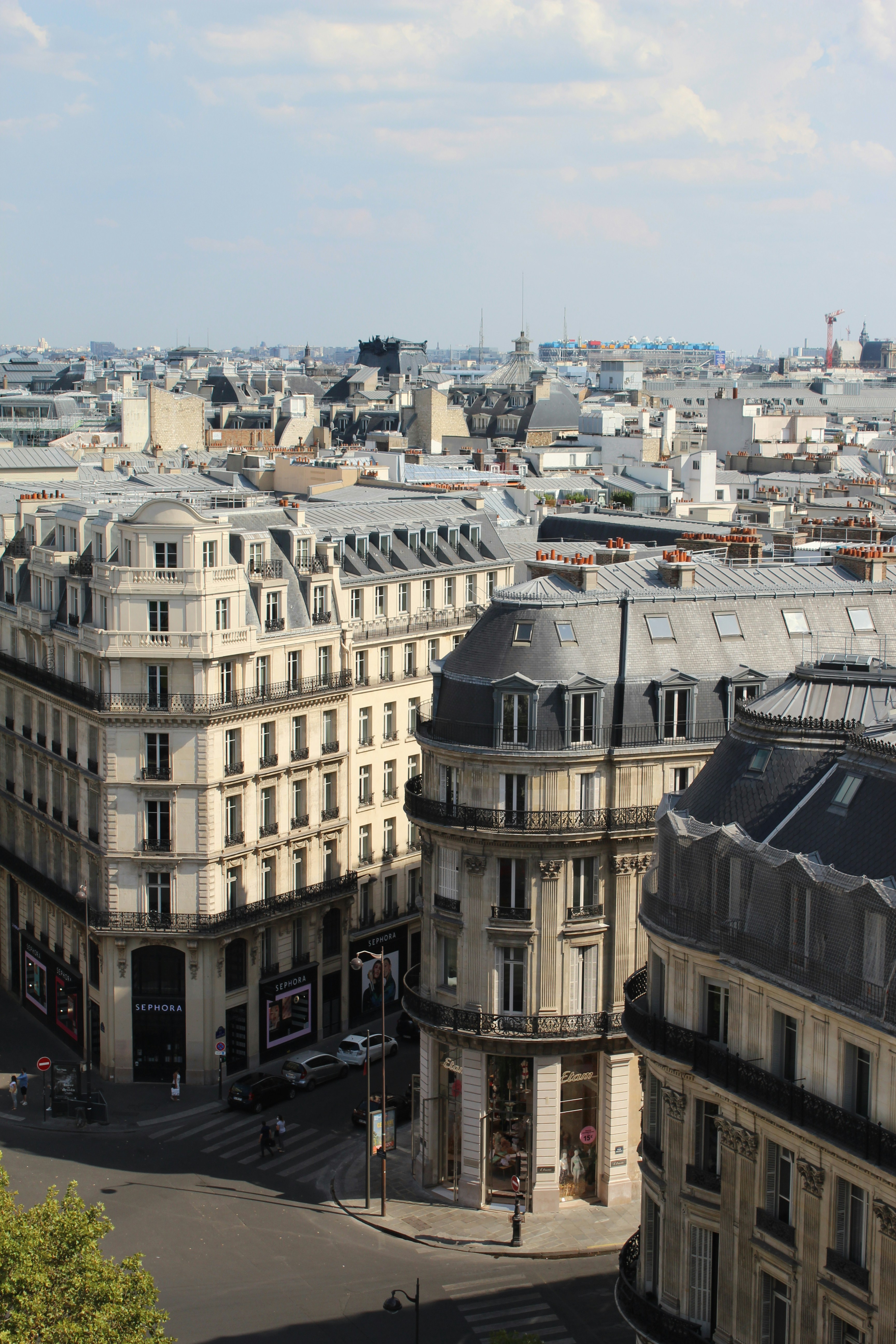 View of Parisian rooftops featuring classic architecture, with a hint of modernity in the background. The scene captures the essence of urban life.