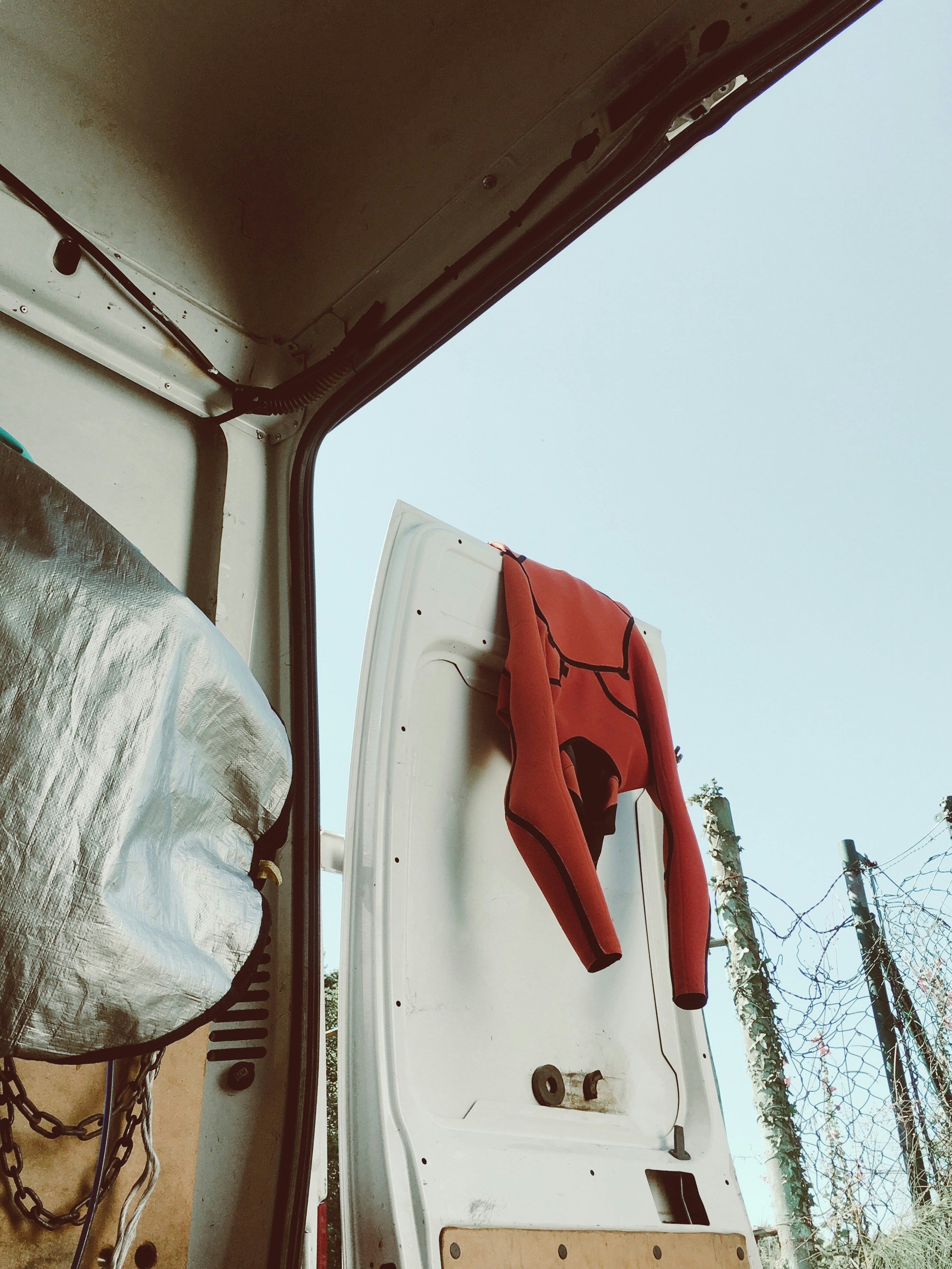 Red Garment on a White Van Door: Quiet Morning Light Inside a Cargo Van