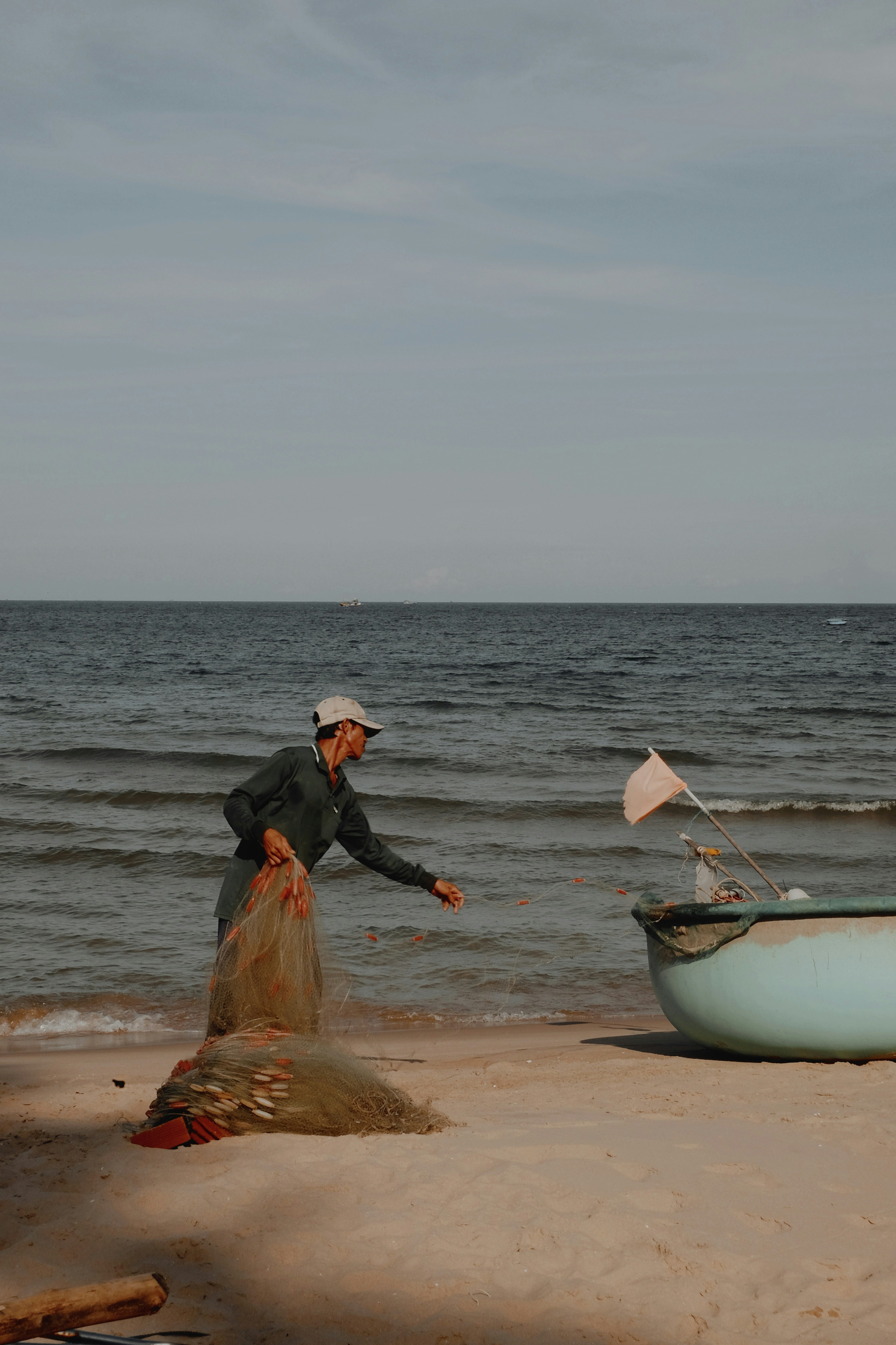 Tidework at the Shore: Fisherman with Net by a Quiet Boat