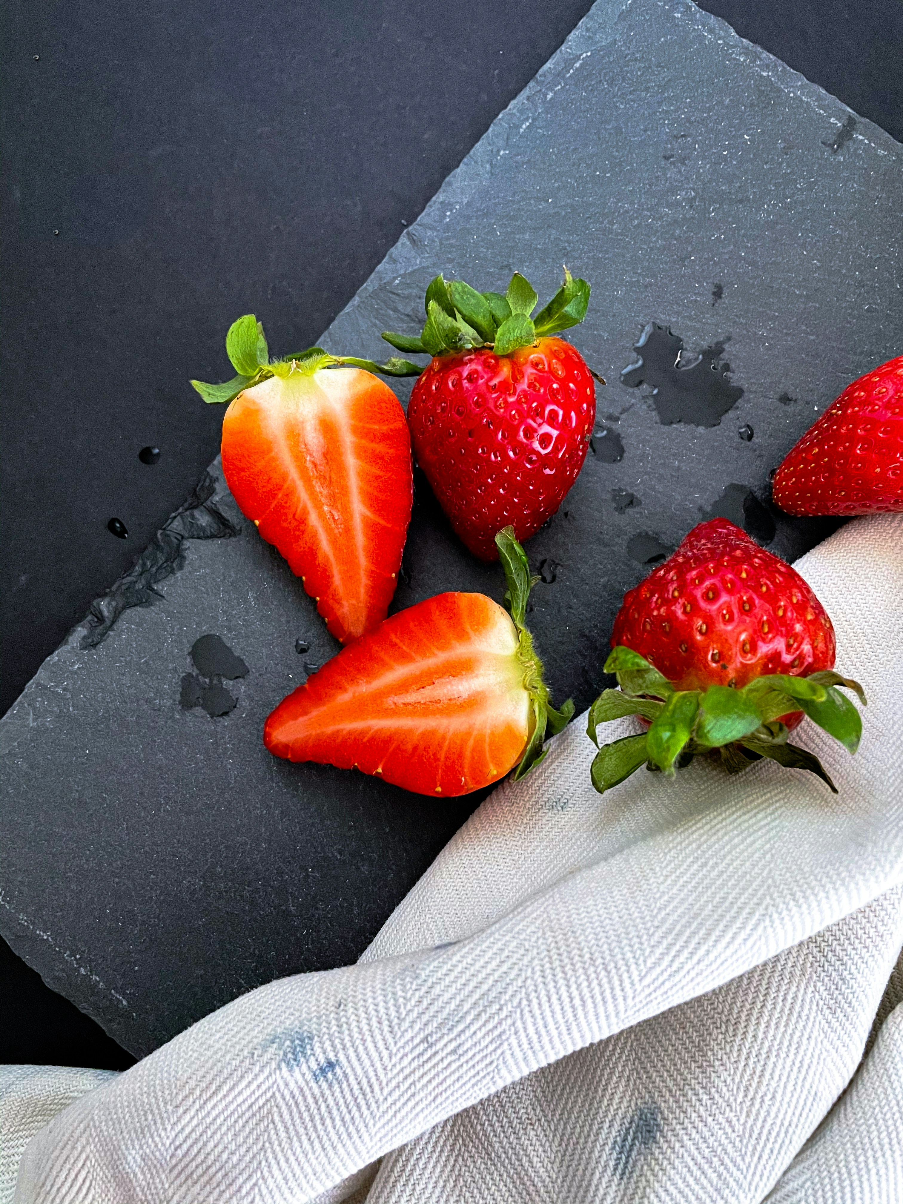 Crimson Halves on Slate: A Close-Up of Fresh Strawberries with Linen