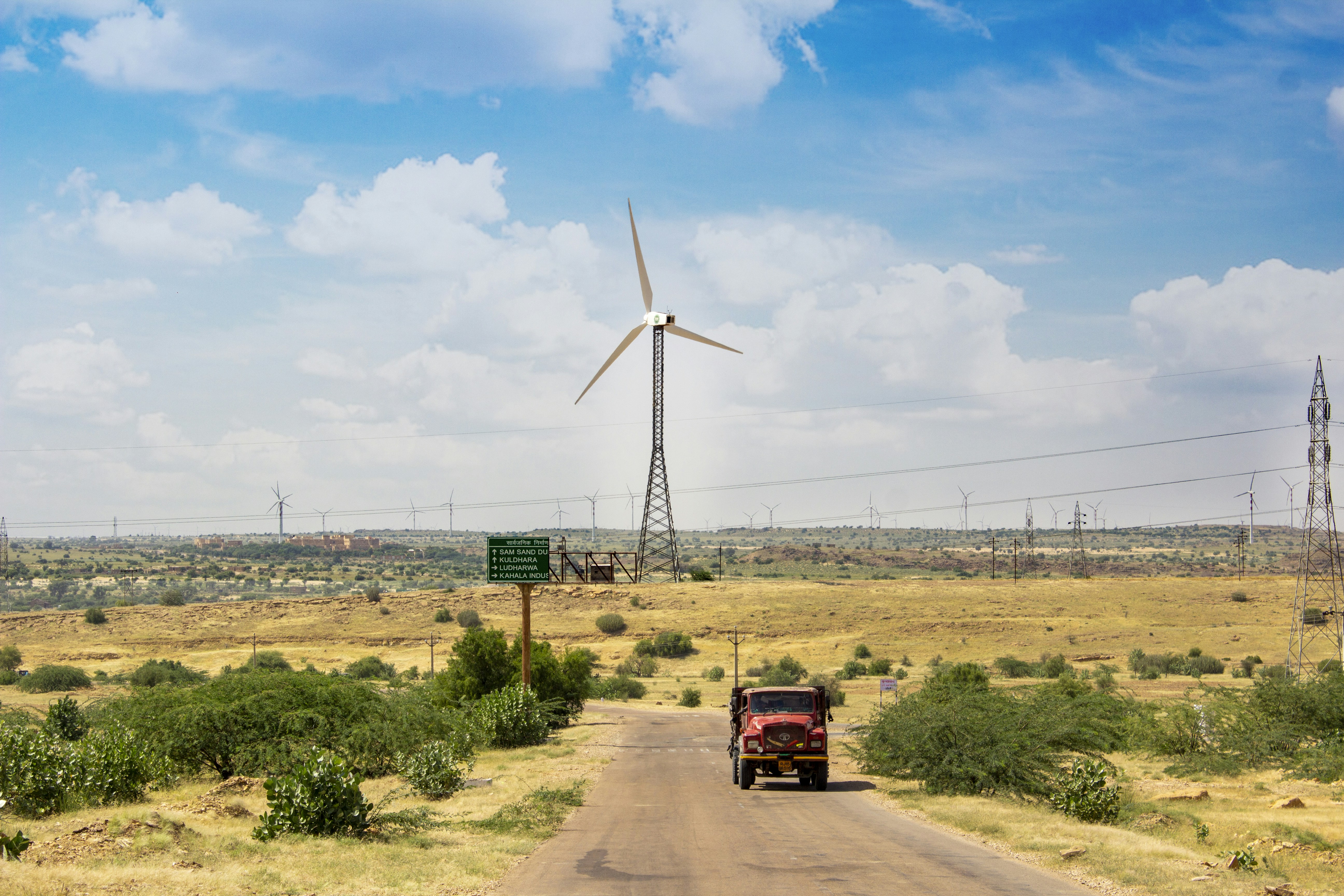 Dust Road Symphony: Red Jeep, Wind Turbine, and Endless Plains
