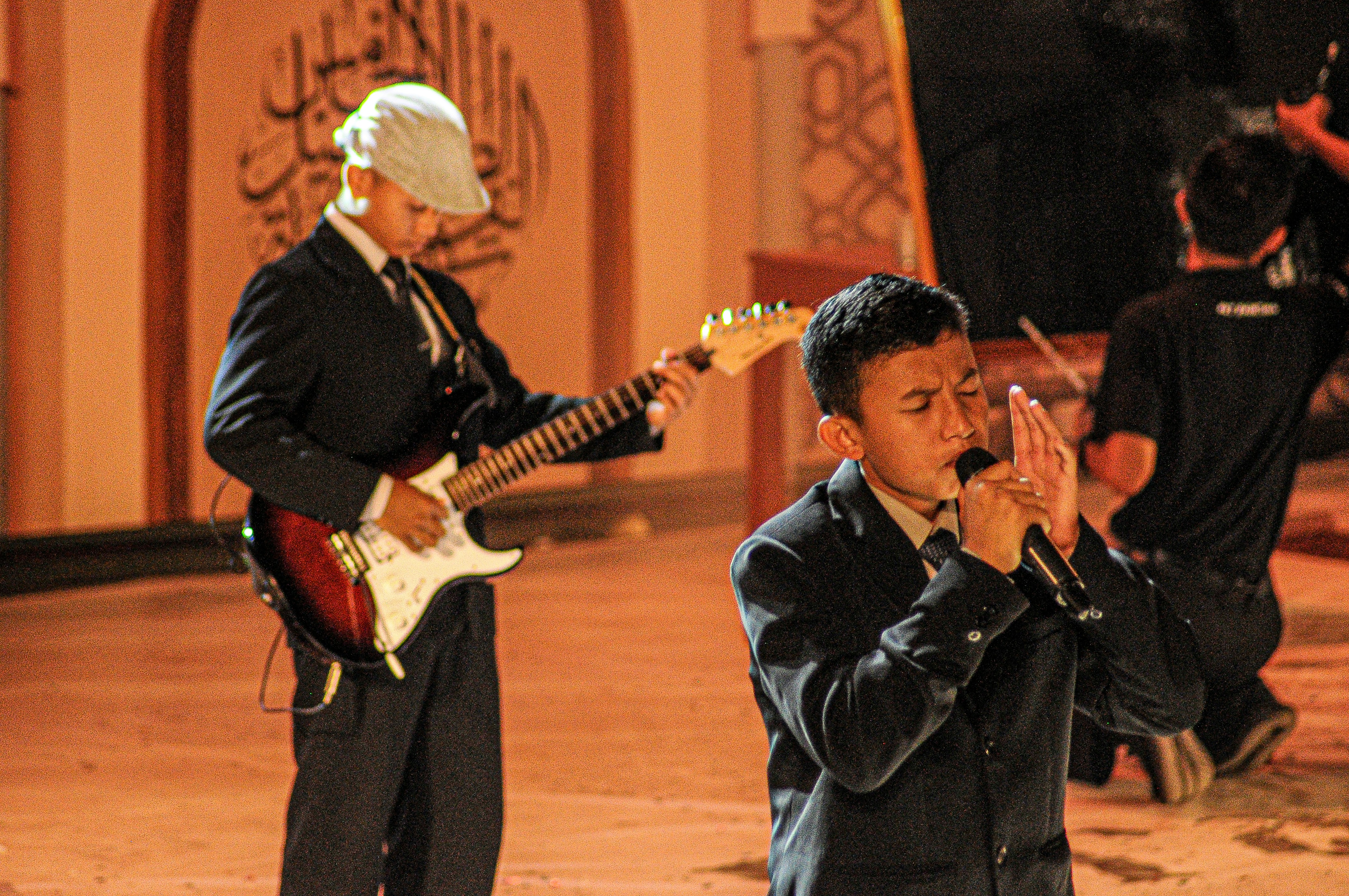 Amber Spotlight Serenade: A vocalist anchors the stage while a guitarist threads a melody.