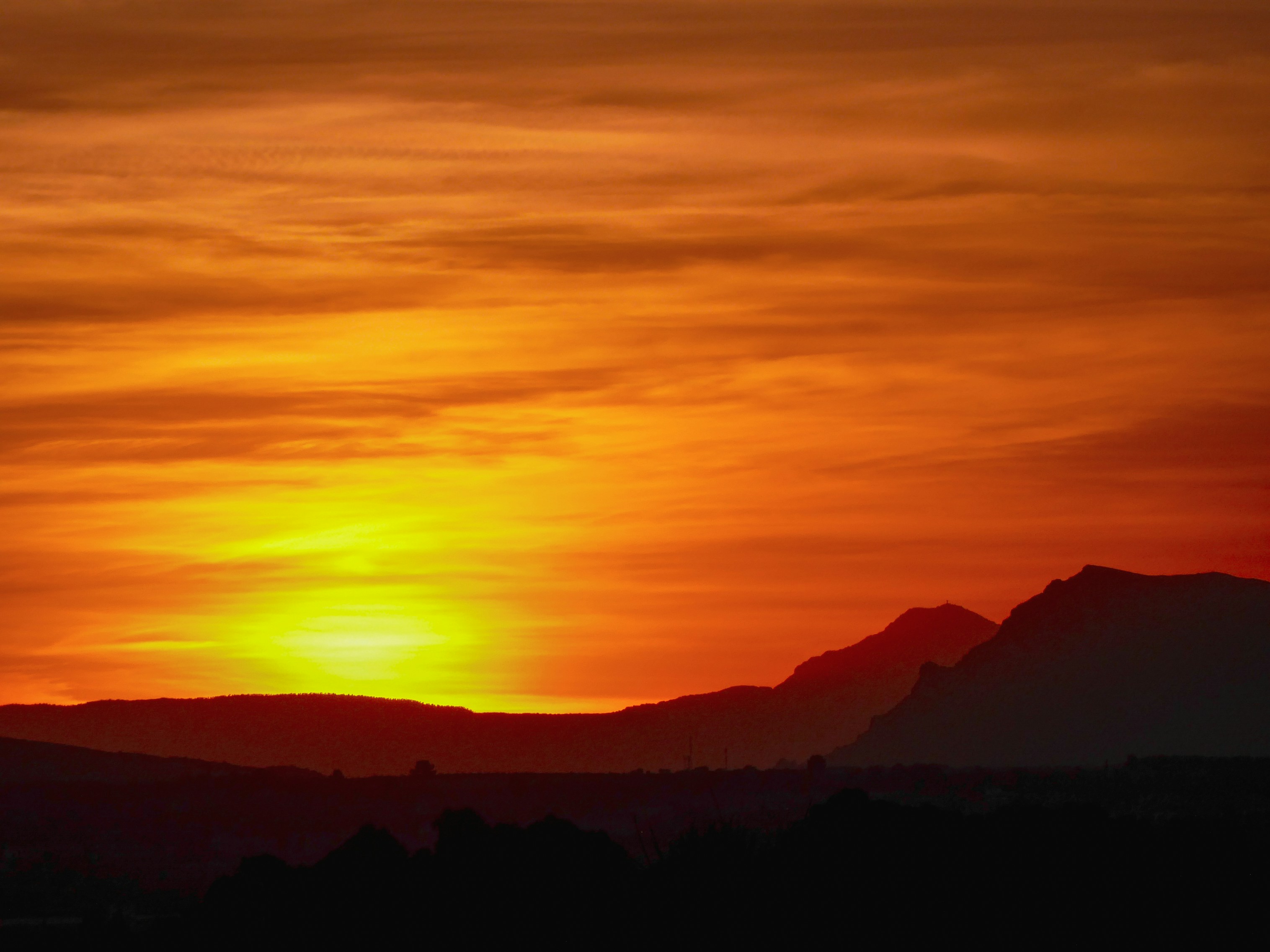 Vibrant sunset casting warm colors over silhouetted hills near Torrevieja.