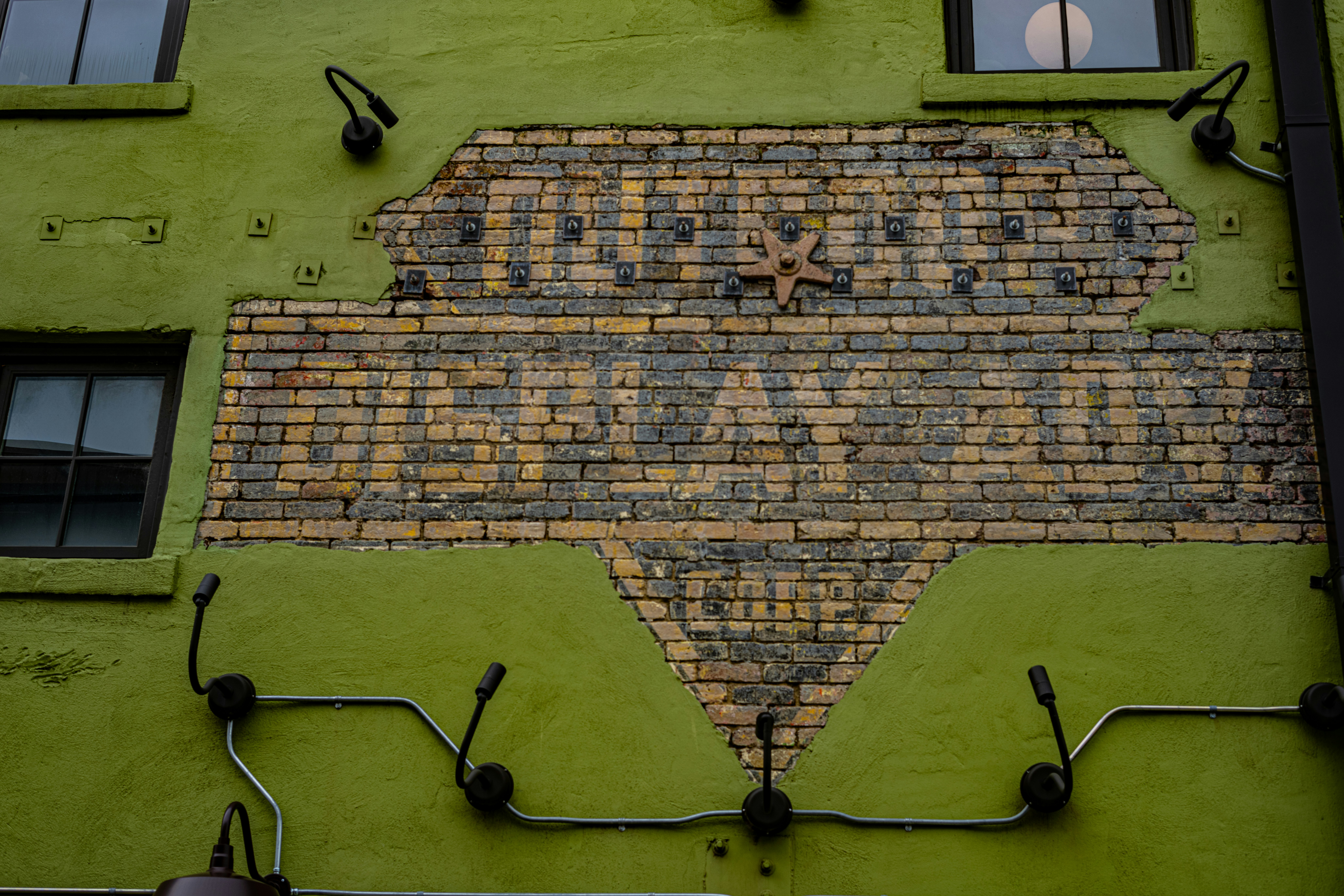 Green Brickwork Landmark: Old Sign Illuminated Beneath a Brick Mosaic